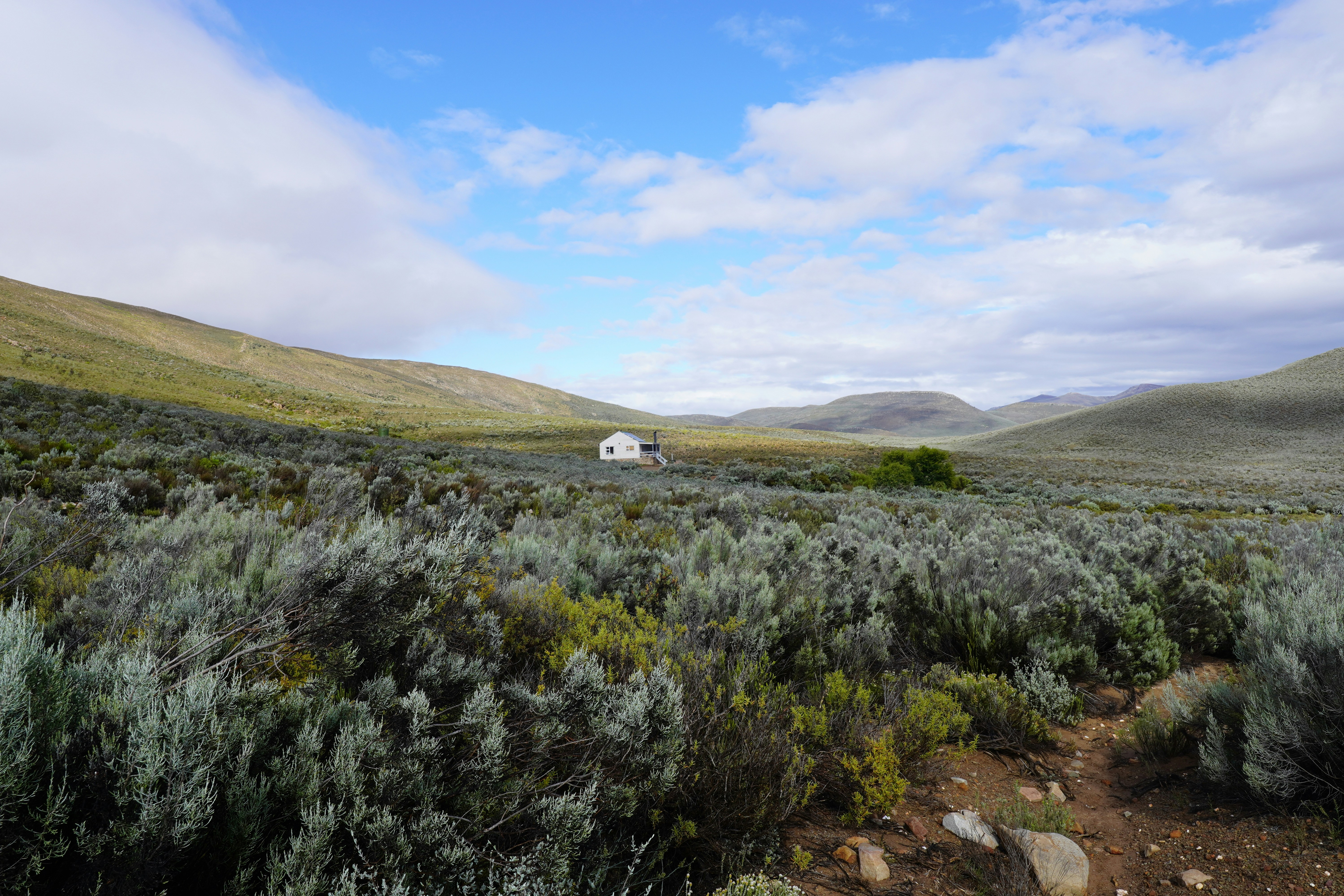 Lone White Cottage Amid Sagebrush Hills Under a Wide Prairie Sky