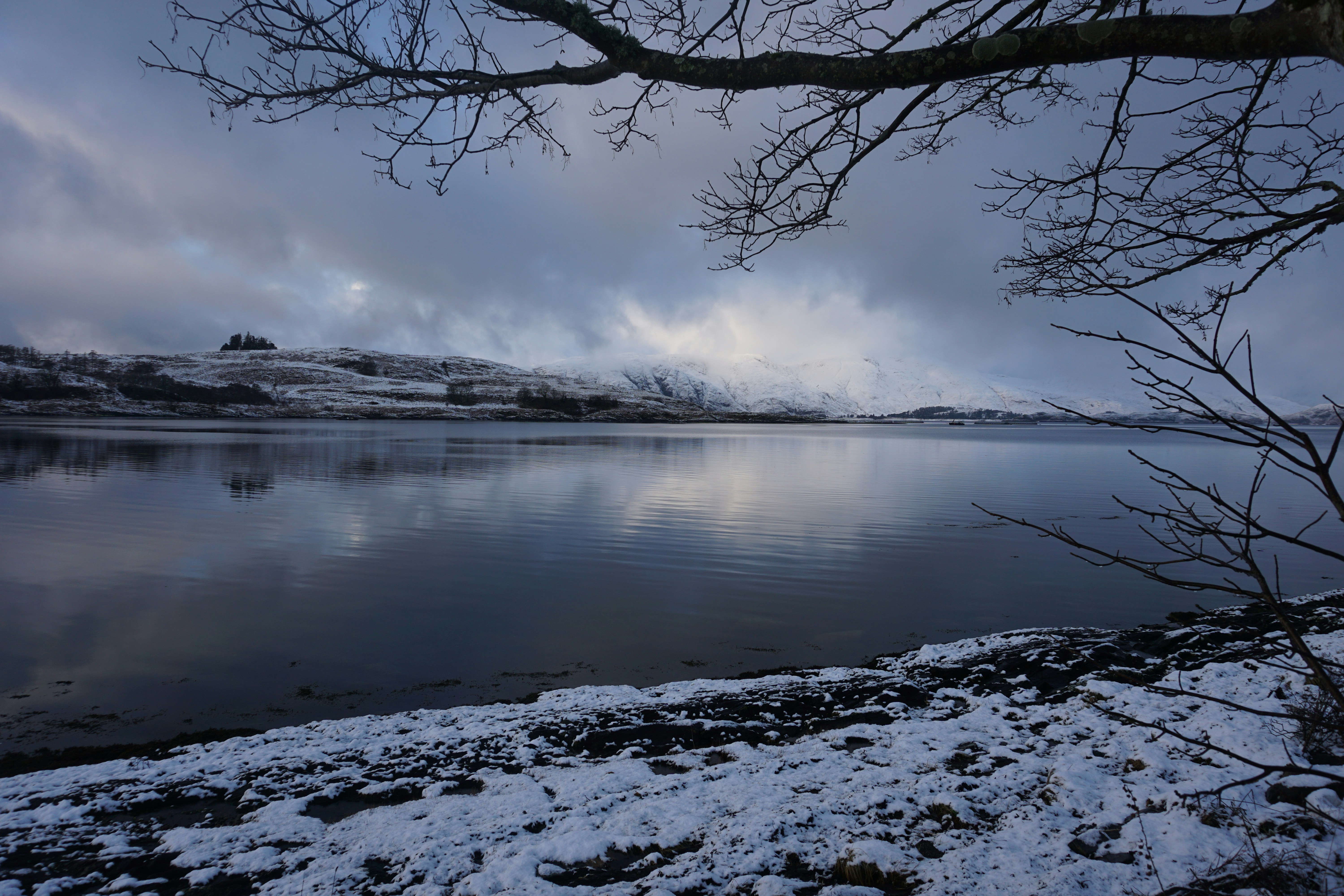 Distant House on a Snow-Kissed Lakeside Under a Brushed-Blue Sky