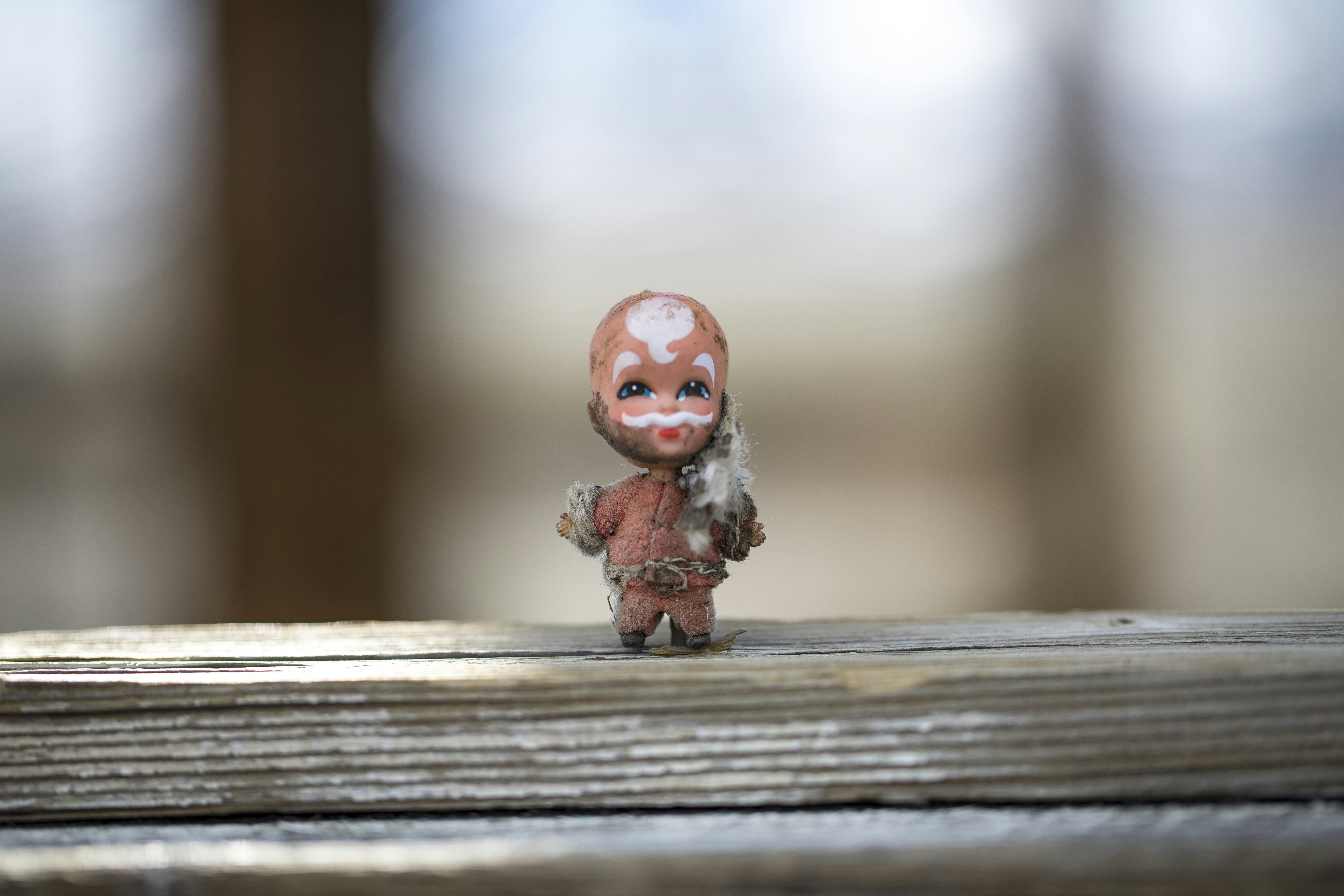 Tiny Figurine on Weathered Rail, Quietly Framed by Soft Bokeh