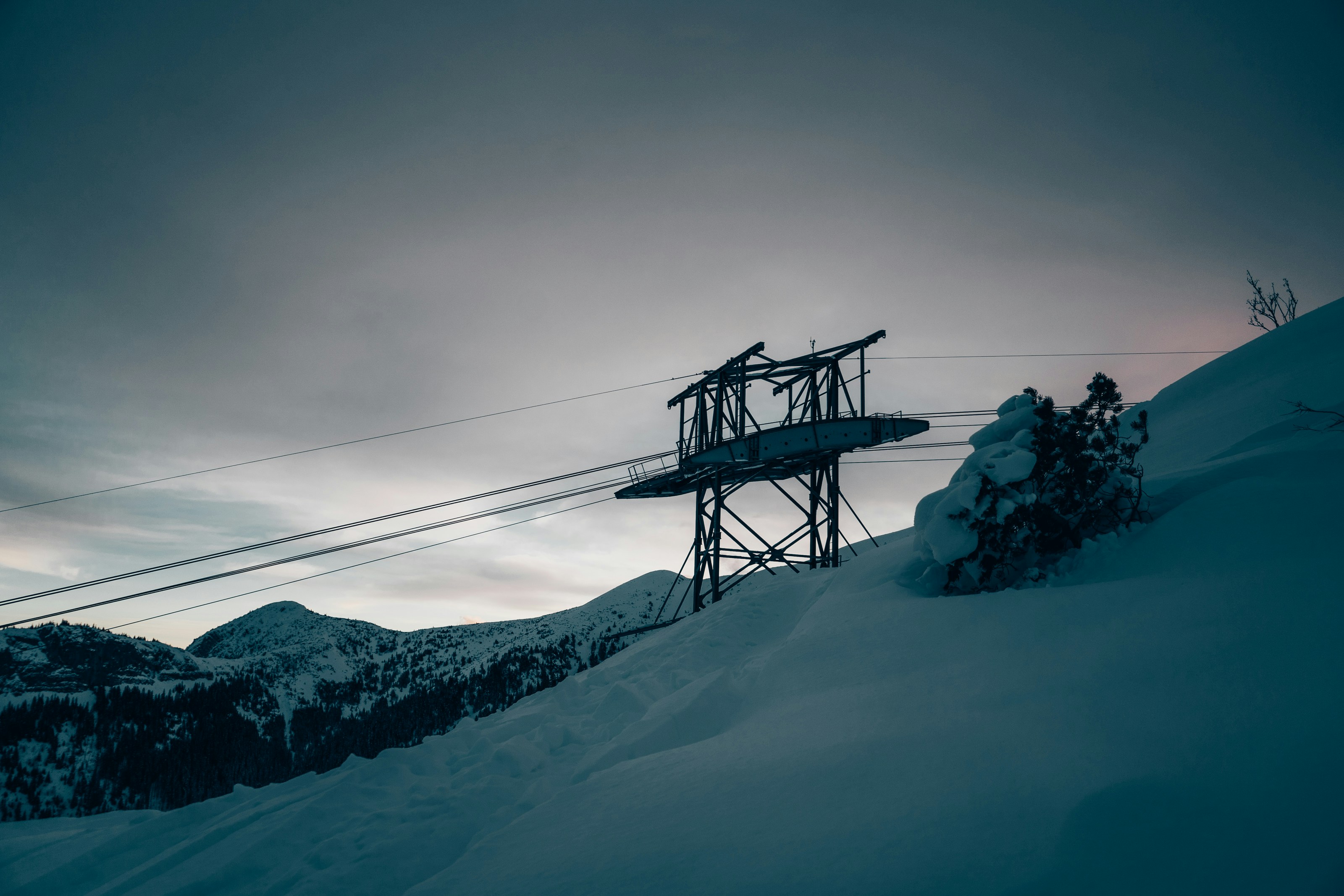 Indigo Dusk Over a Lone Ski Lift Tower on a Snowbound Ridge