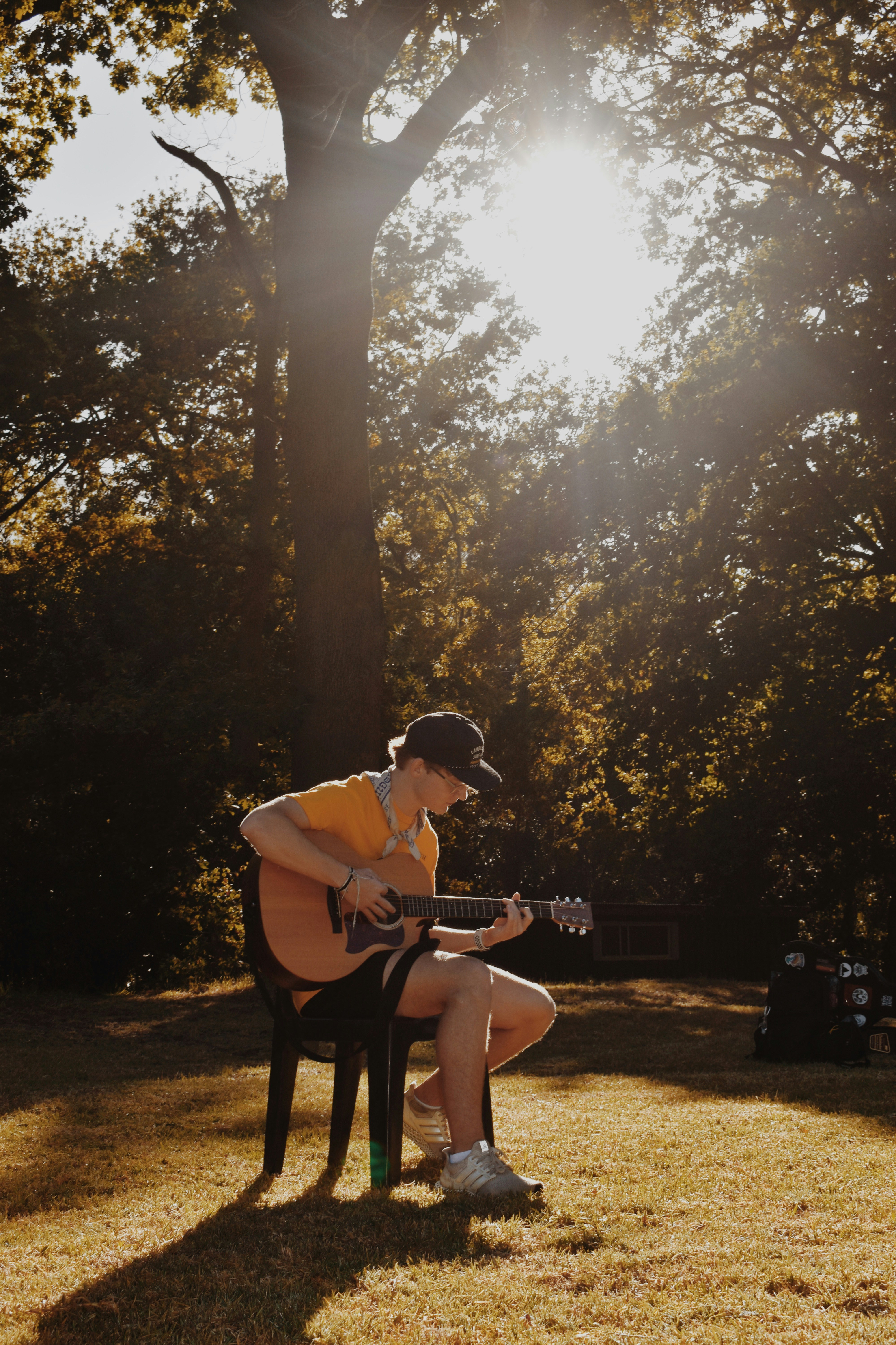 person worshiping with light shining down | a woman sitting in a chair playing a guitar
