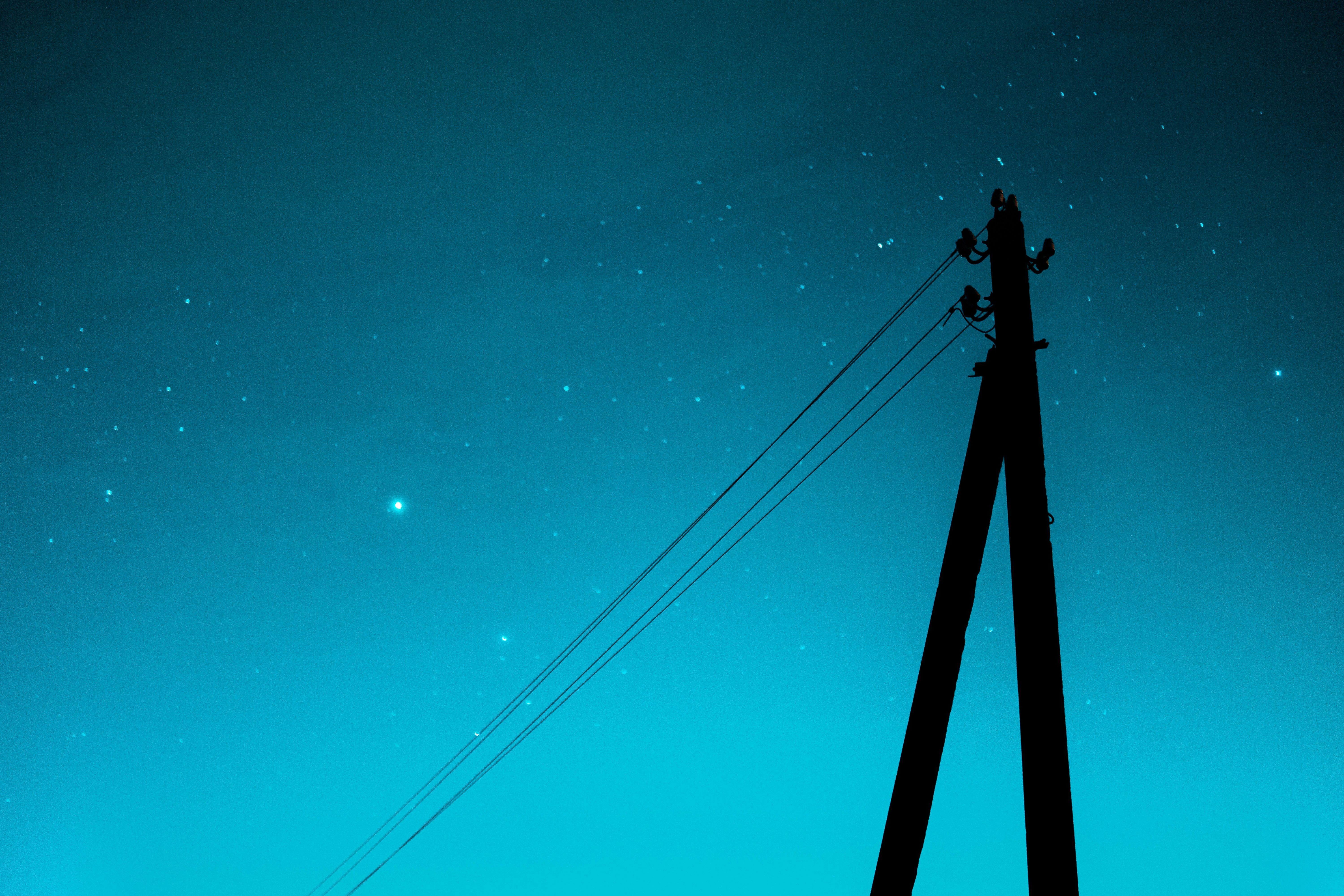 Silhouette of a Transformer-style Utility Pole Reaching Toward a Starry Sky