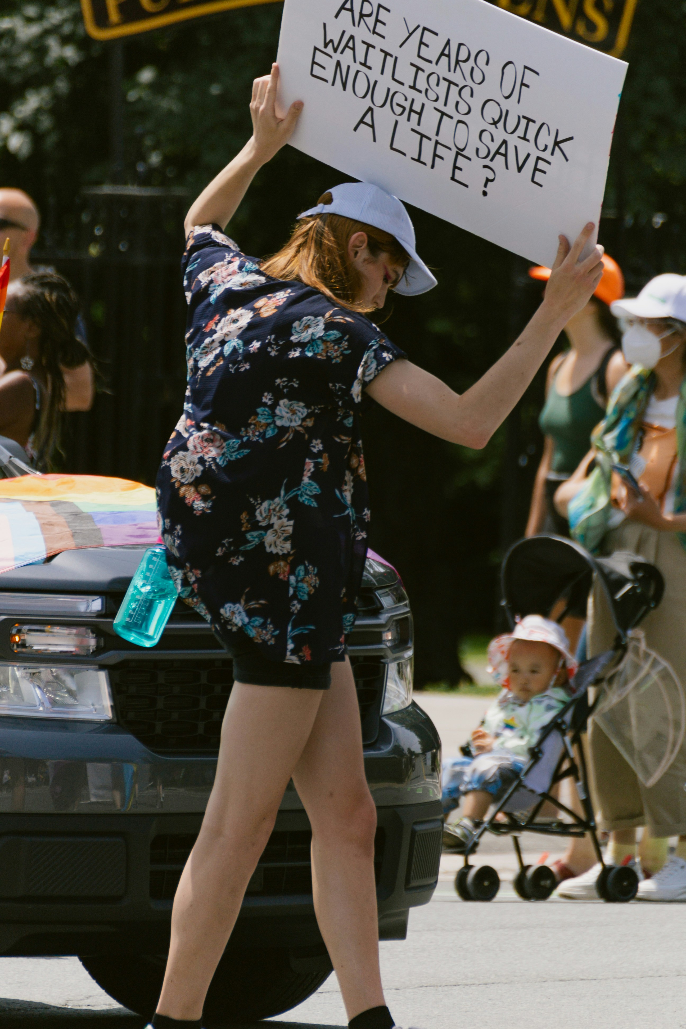 Floral-Clad Protester Raises a Sign by a Parked Vehicle