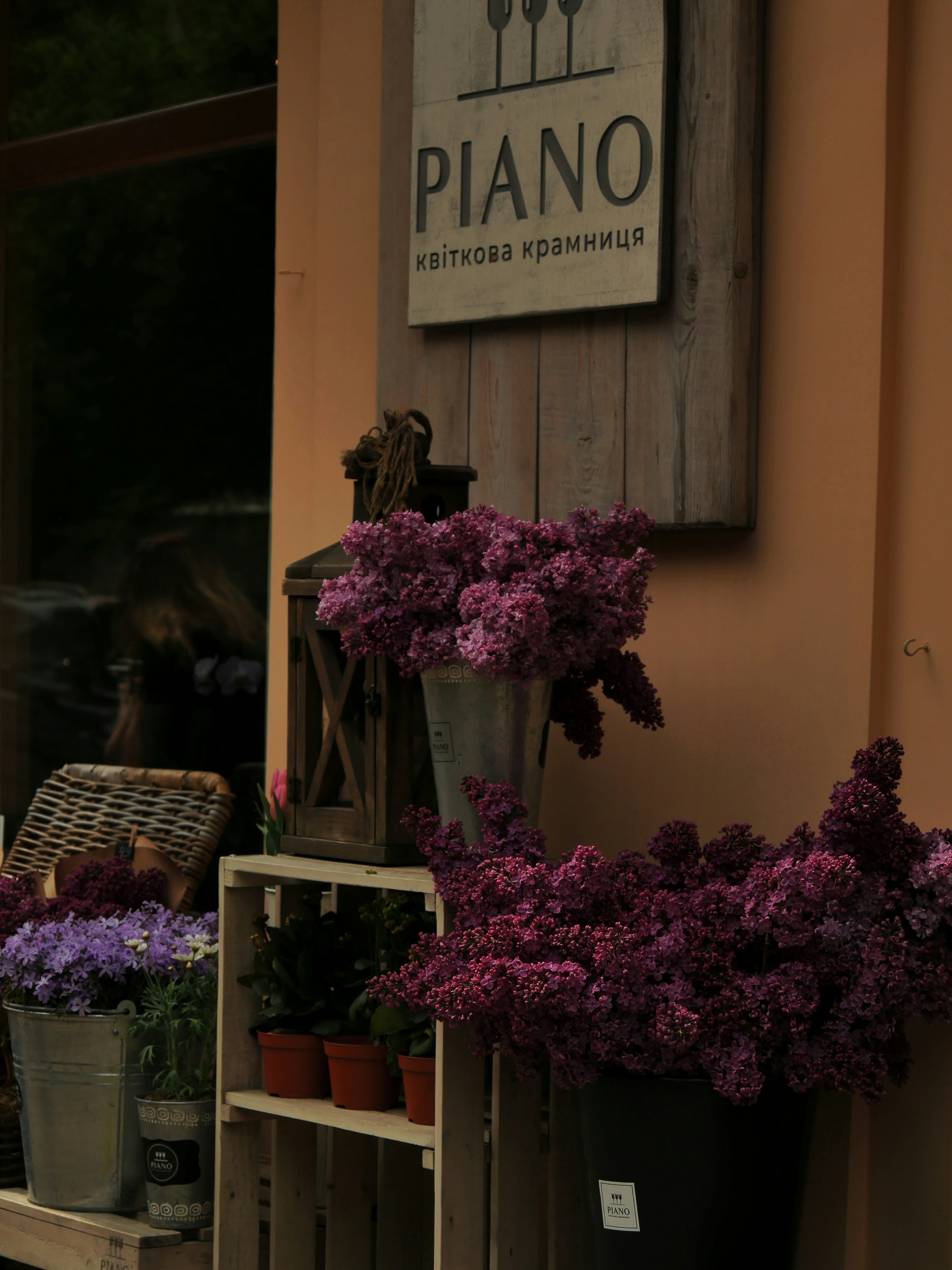 Lilac Frontage: Pots, Crates, and a Weathered PIANO Sign