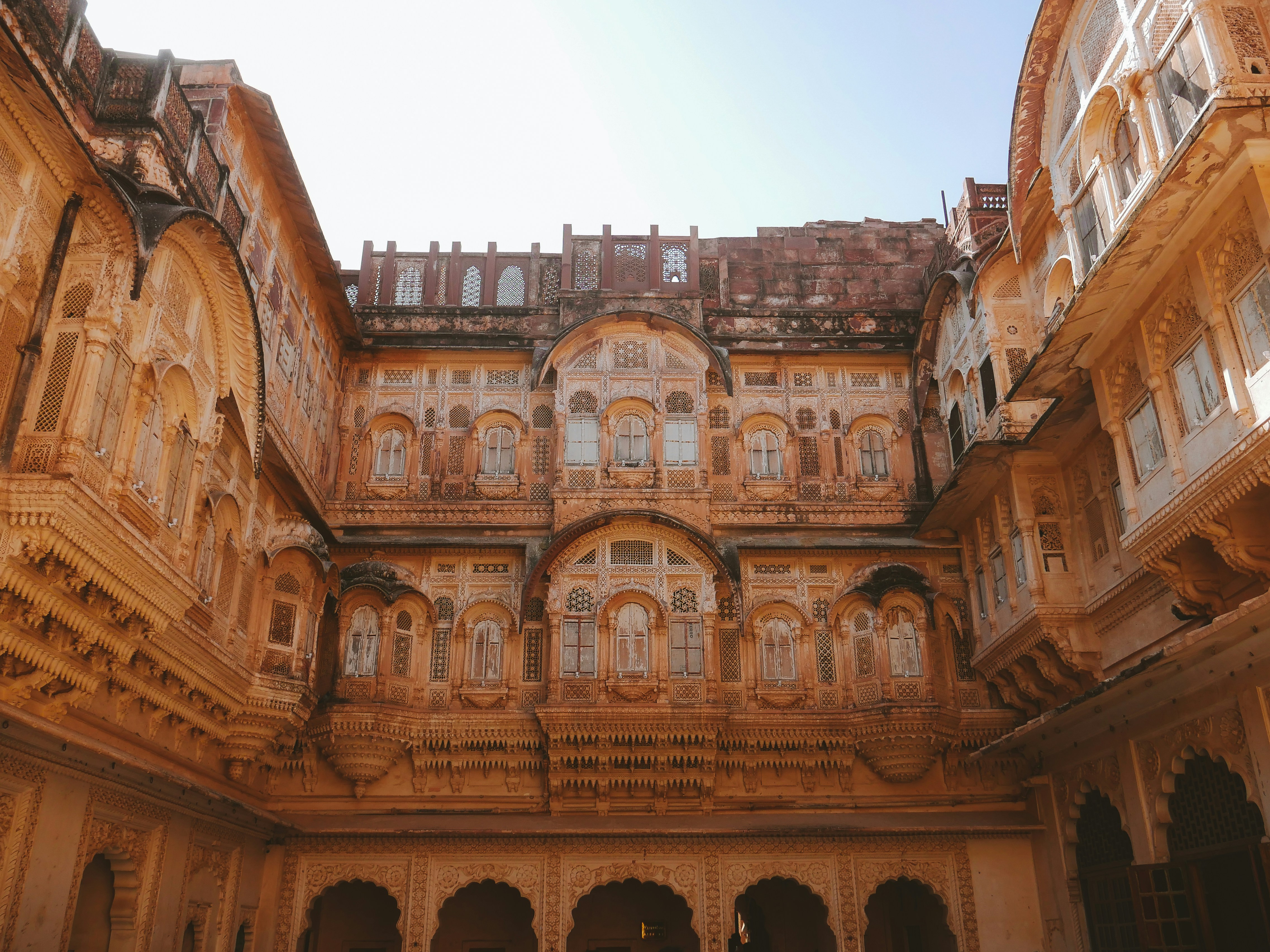 Ornate courtyard with detailed stone carvings under a clear blue sky.