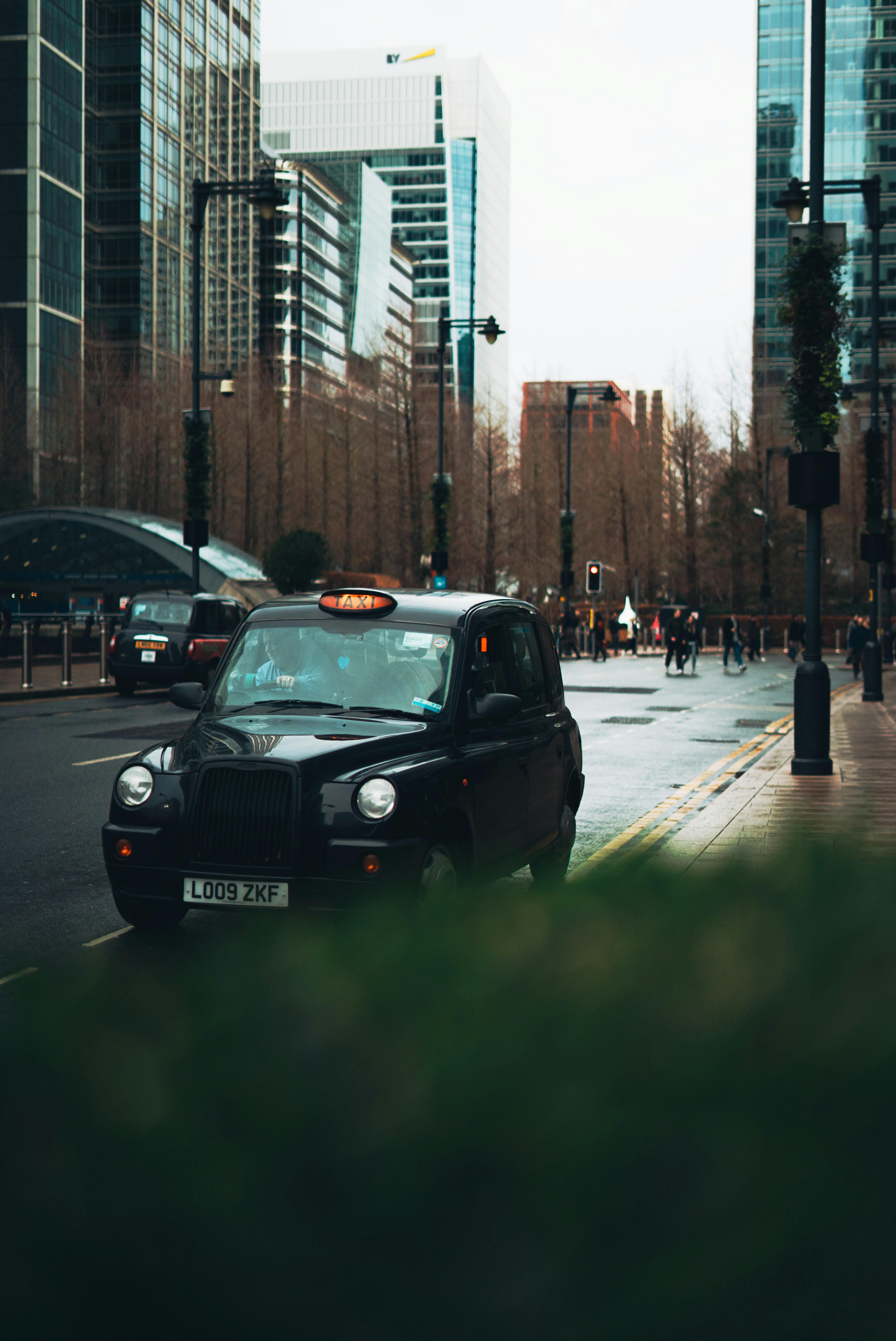 A taxi cab driving down a street next to tall buildings photo – Free ...