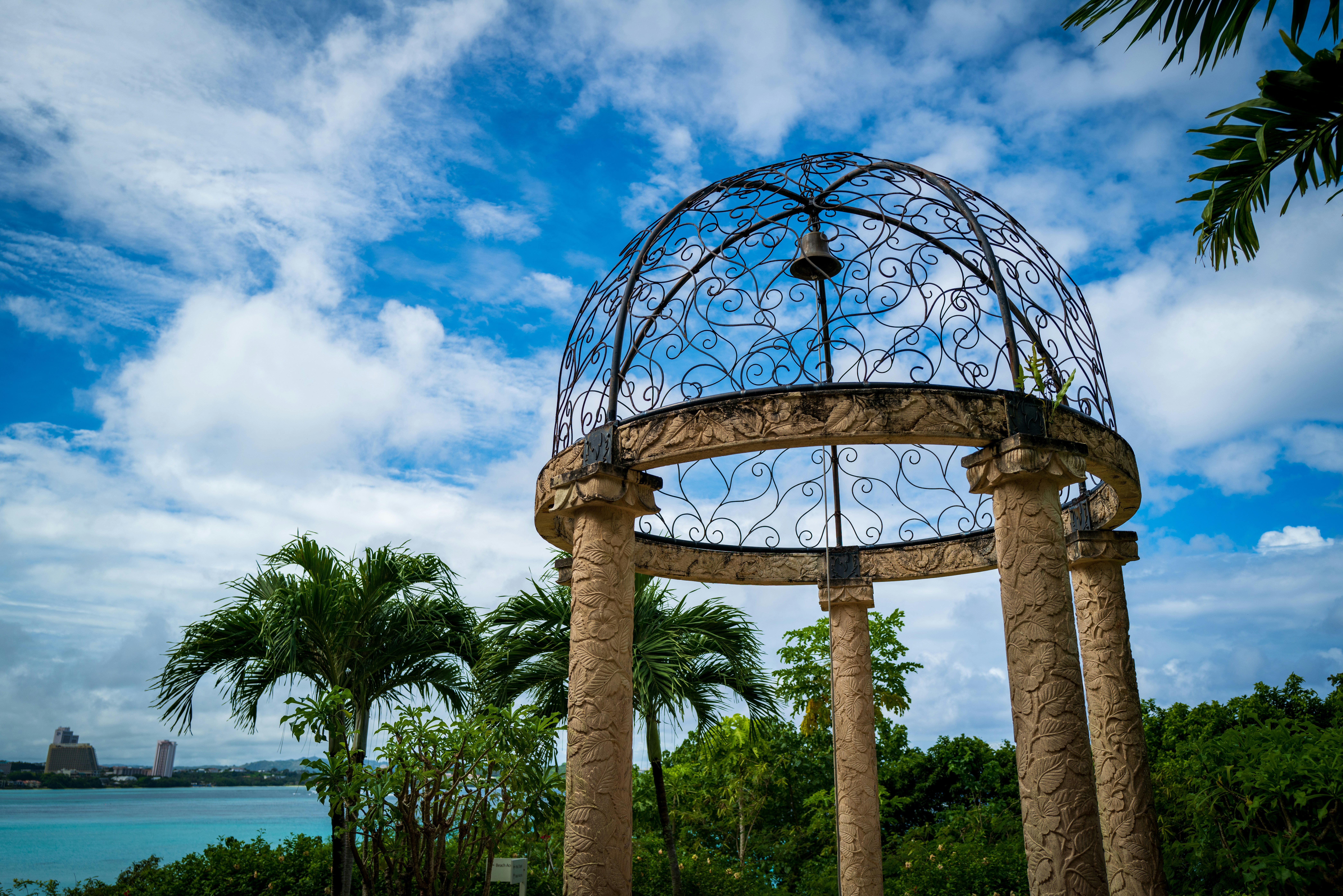 Iron-Domed Gazebo Framed by Palms Against a Turquoise Sea