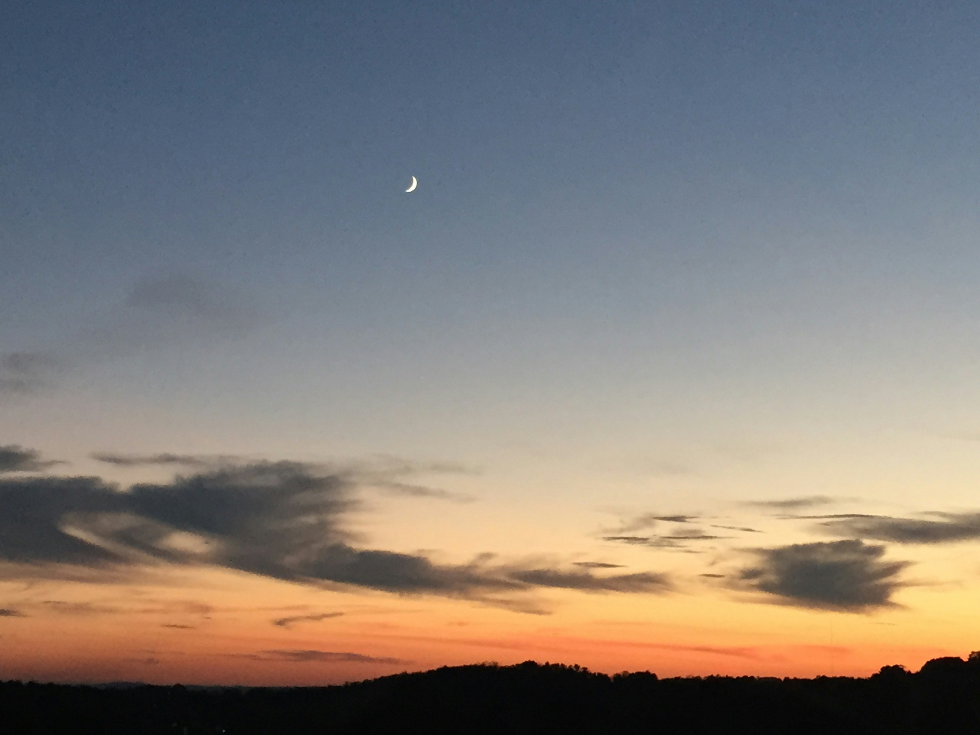 The sun is setting over a hill with a crescent in the sky photo – Free ...