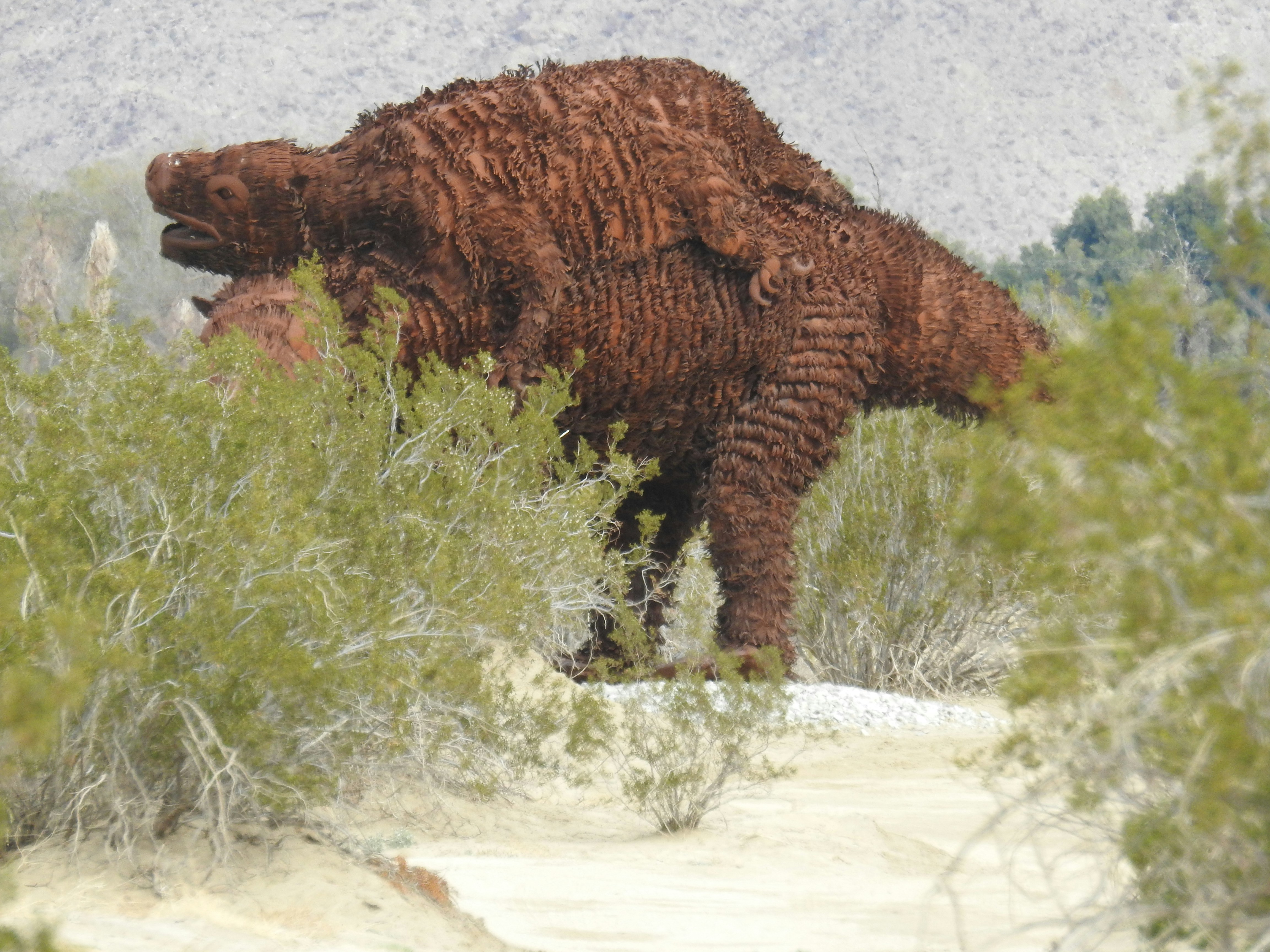 Desert Sentinel: A Woolly Mammoth Statue Amid Scrub
