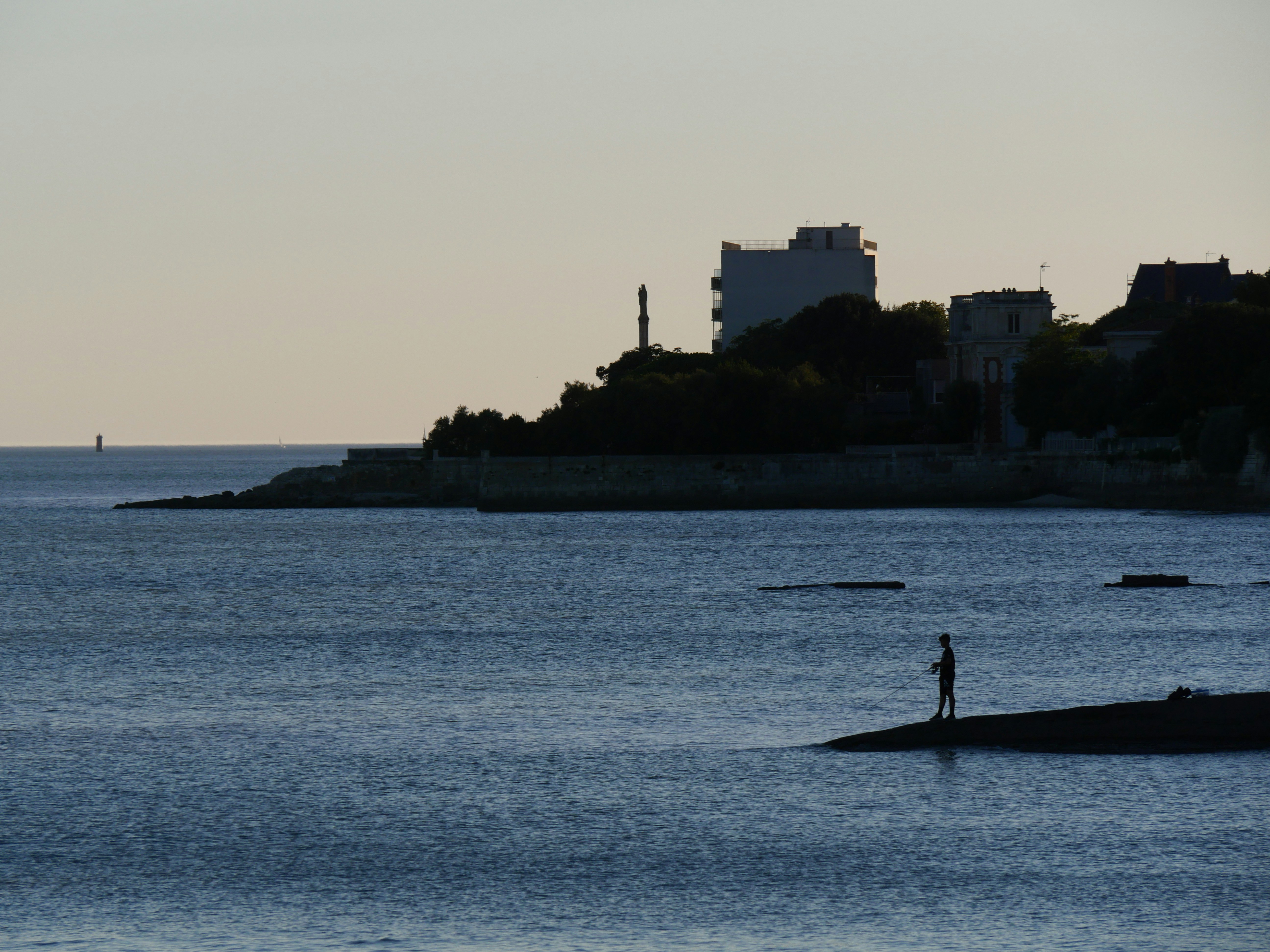 Silhouette on a Dusk Breakwater: Lone Figure by the Quiet Cape