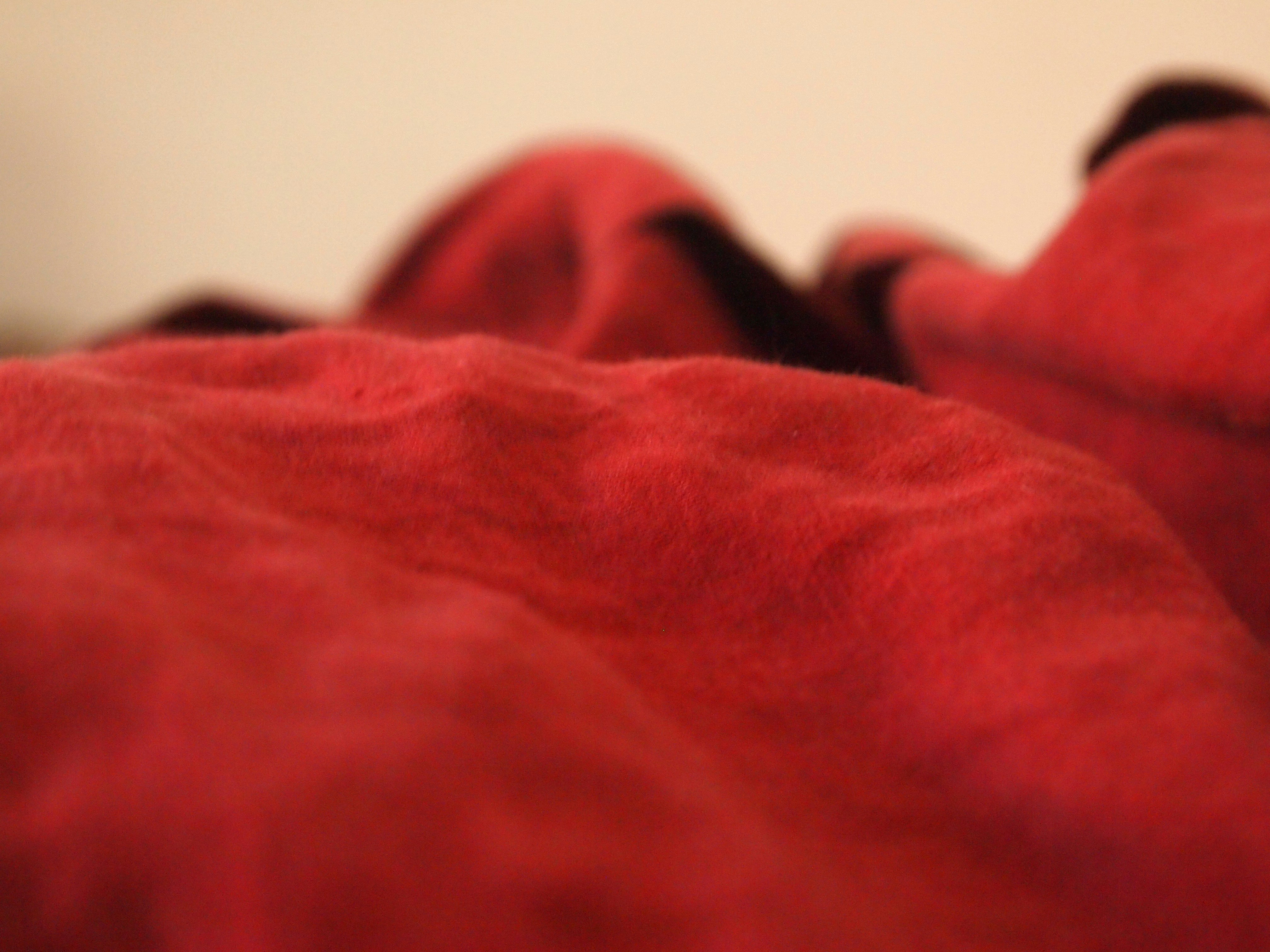 Close-up of soft, textured red fabric, inviting a sense of warmth and comfort.