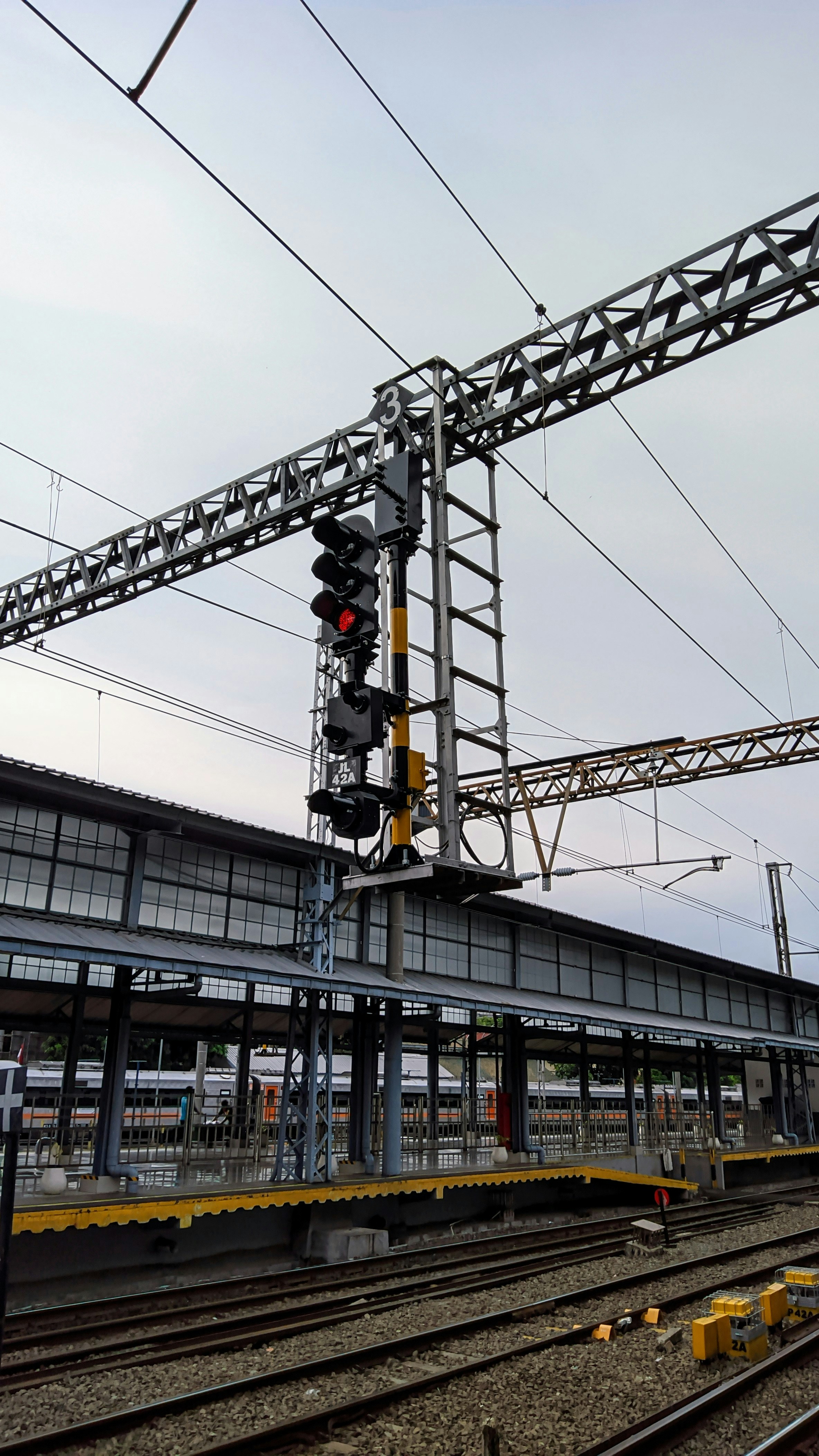 Railway signal post displaying operational lights against a backdrop of a station structure. The intricate design highlights the importance of signaling in train transport.