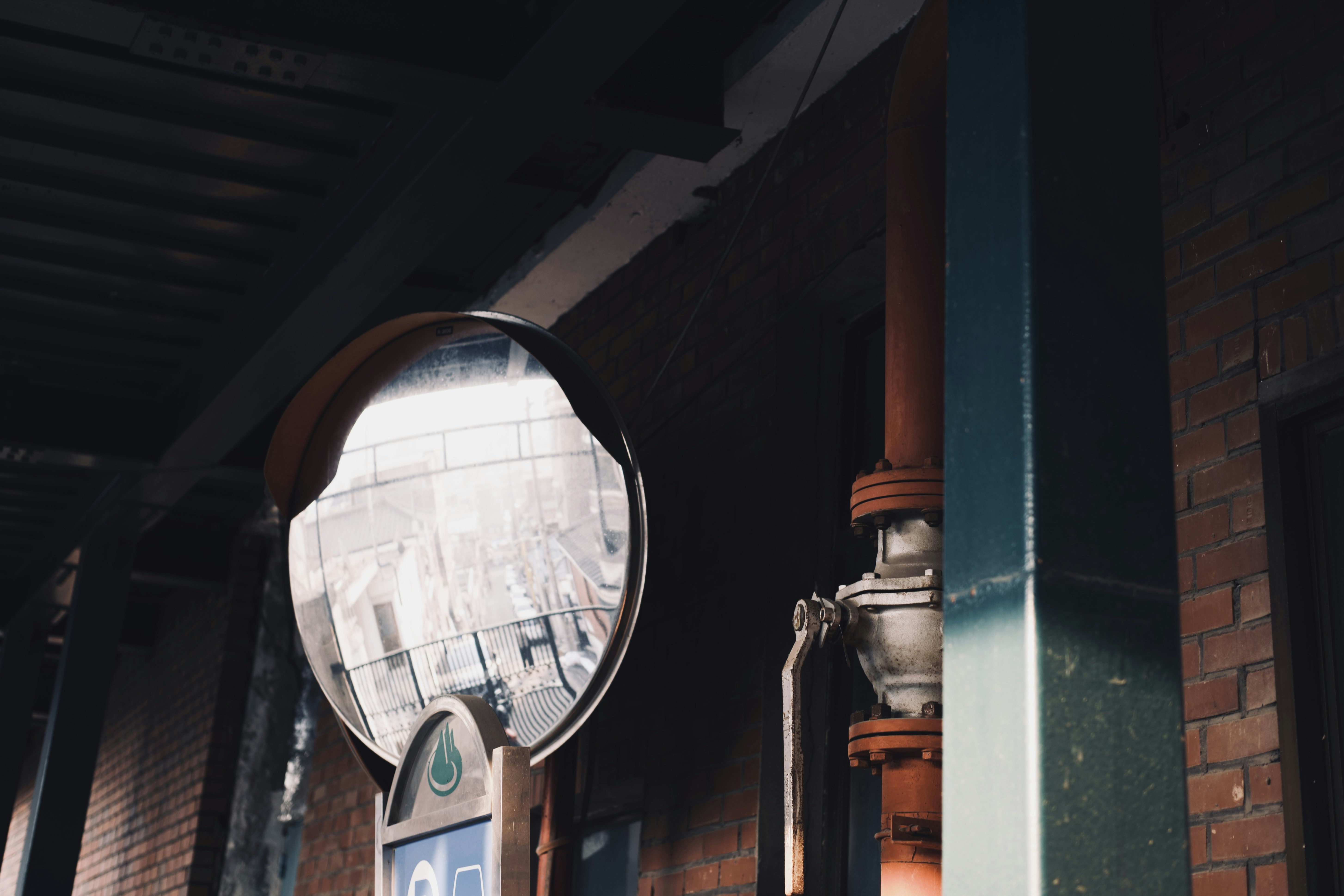 A convex mirror reflects the surrounding architecture and urban elements, capturing the essence of city life. The composition highlights the interplay of light and structure.