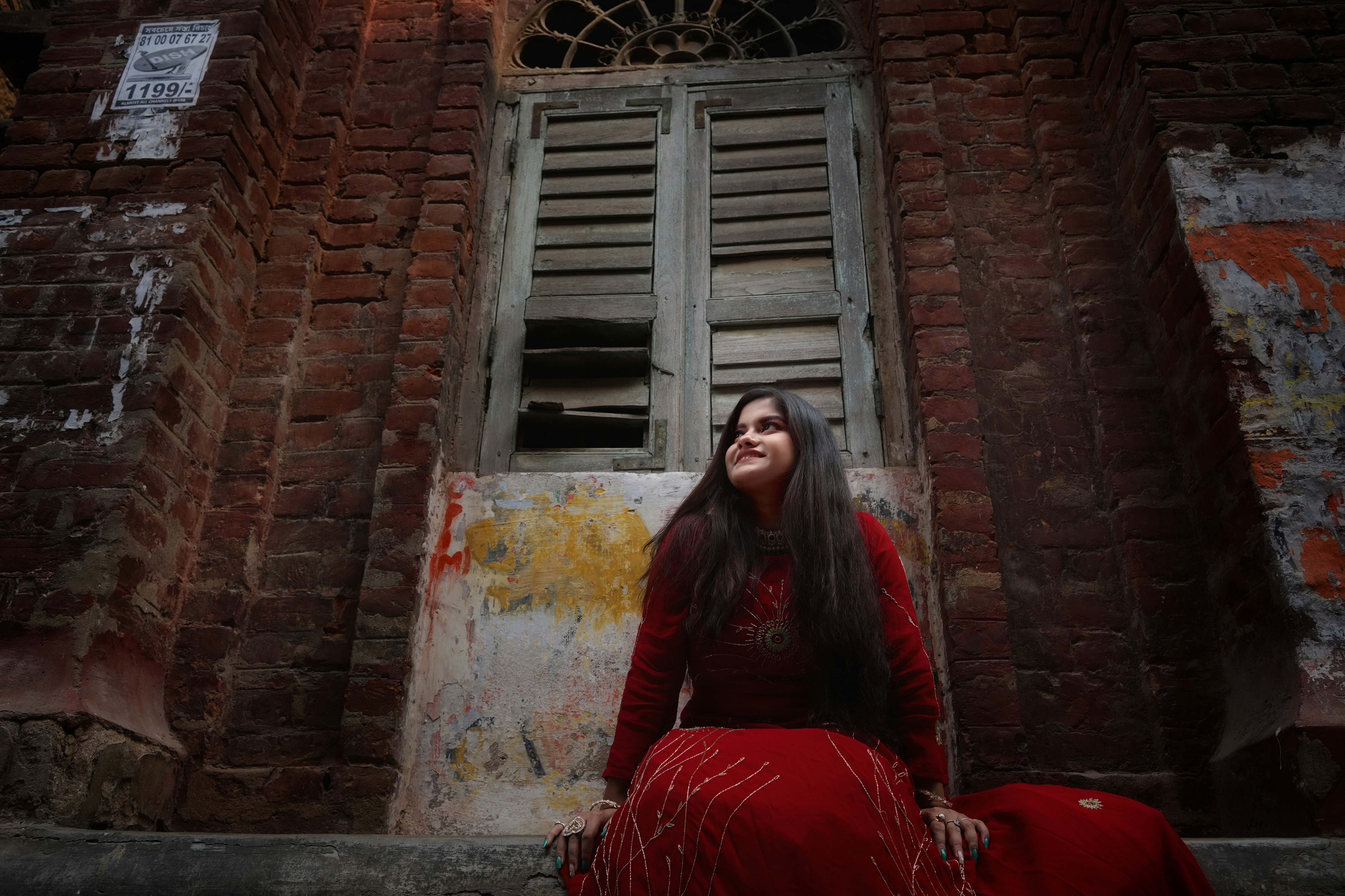 Crimson on Brick: A Solitary Moment by a Weathered Window