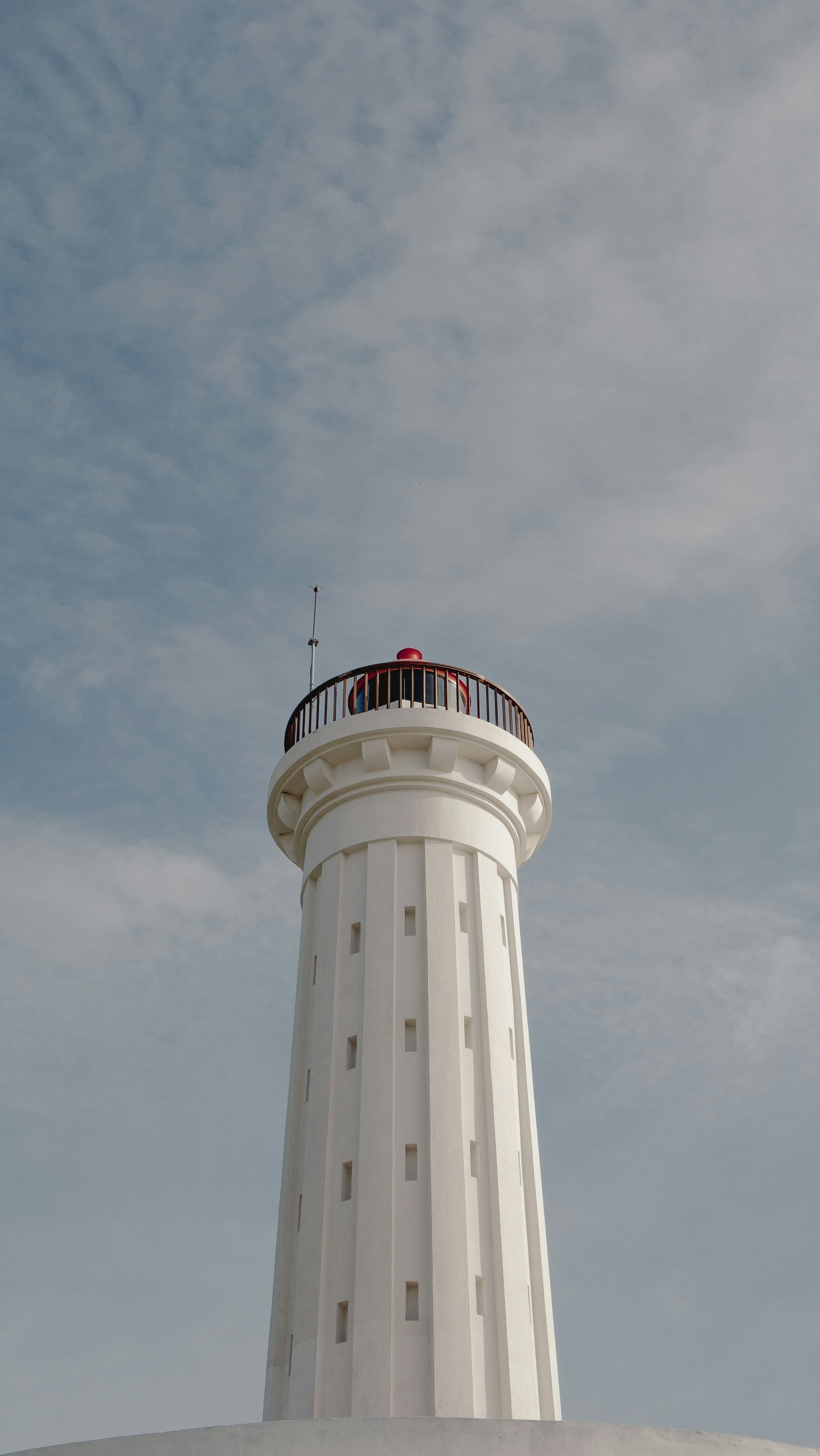 A white lighthouse with a red top on a clear day photo – Free ...