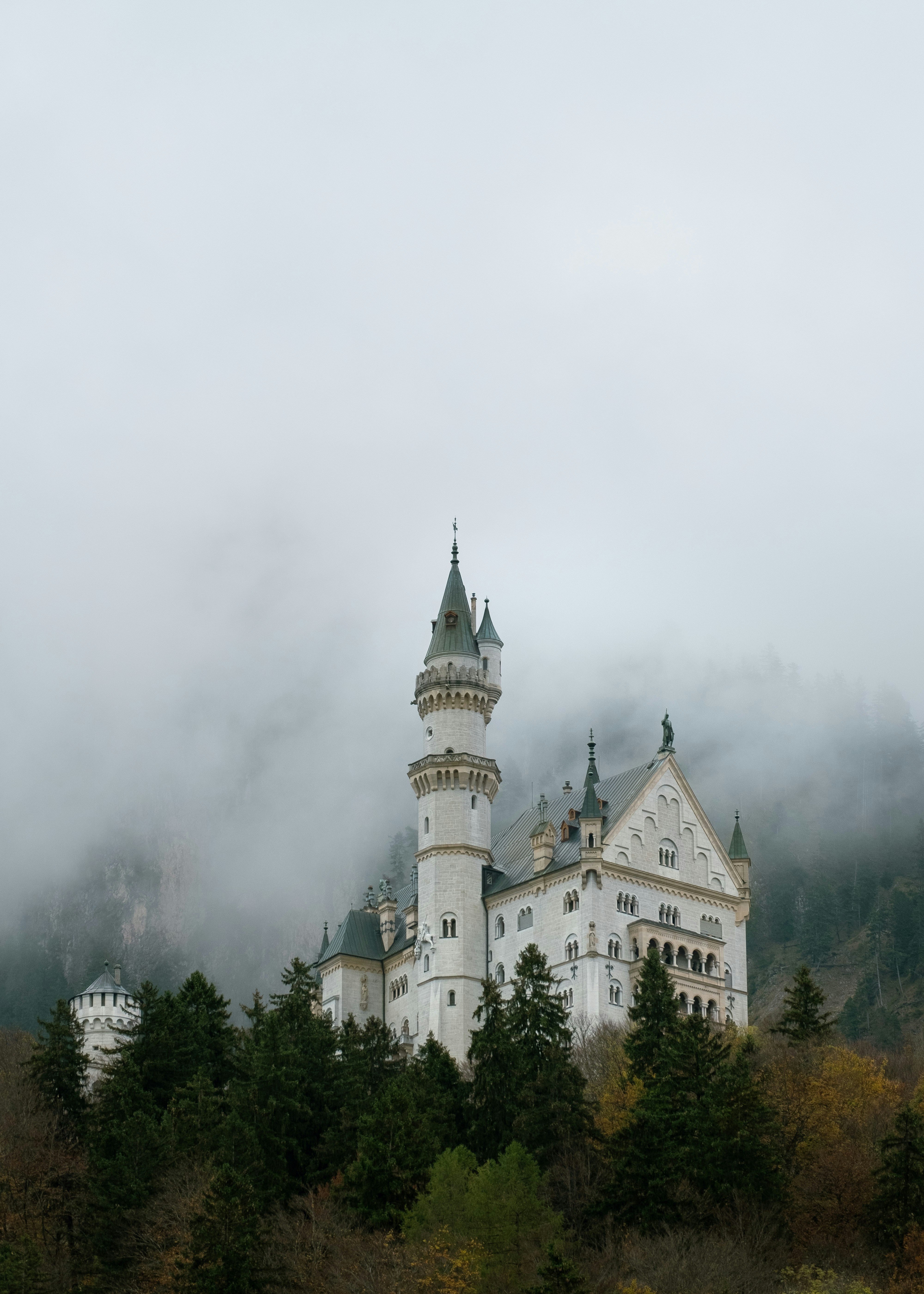 A large white castle sitting on top of a lush green hillside photo ...