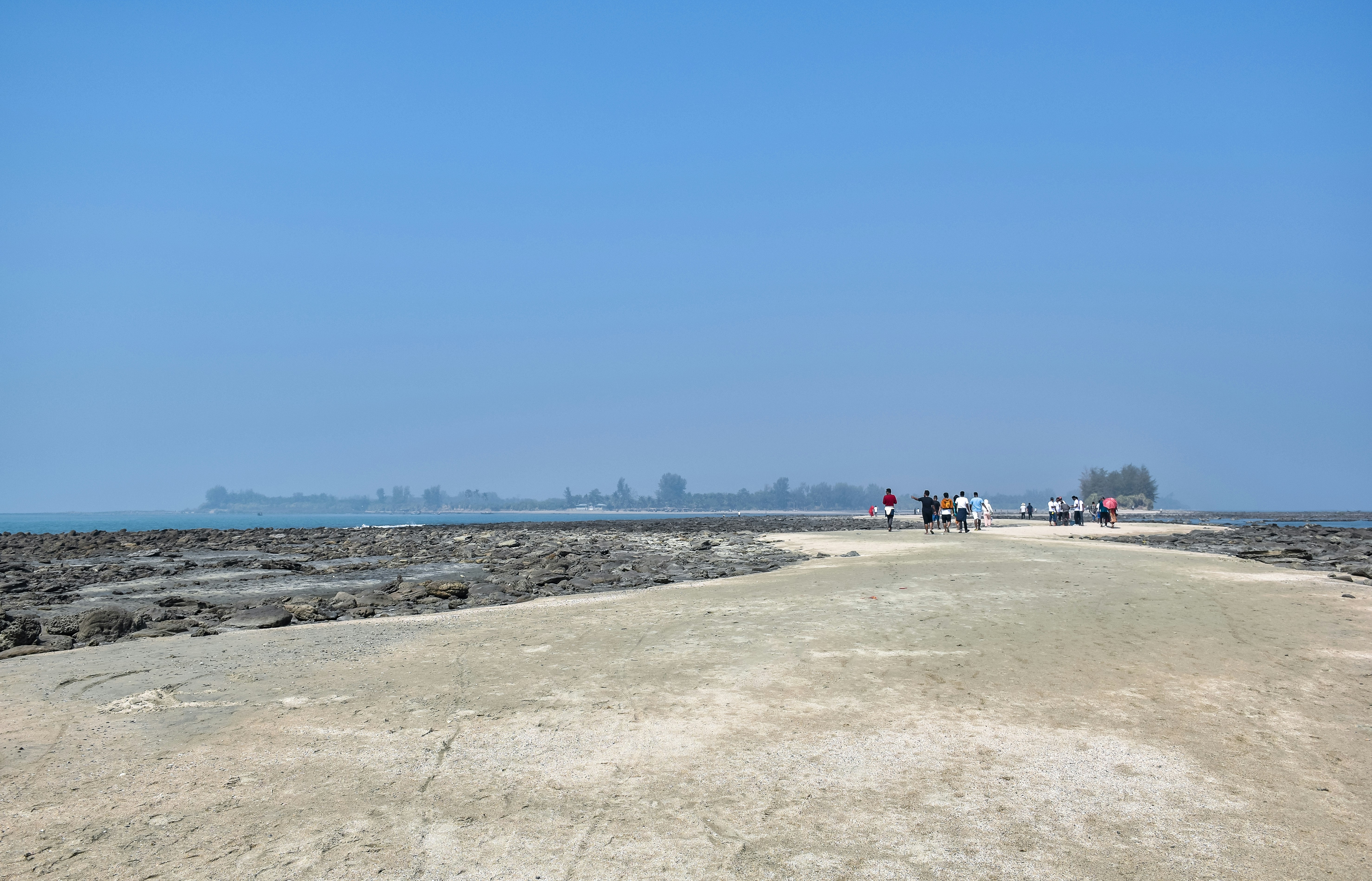a group of people standing on top of a sandy beach