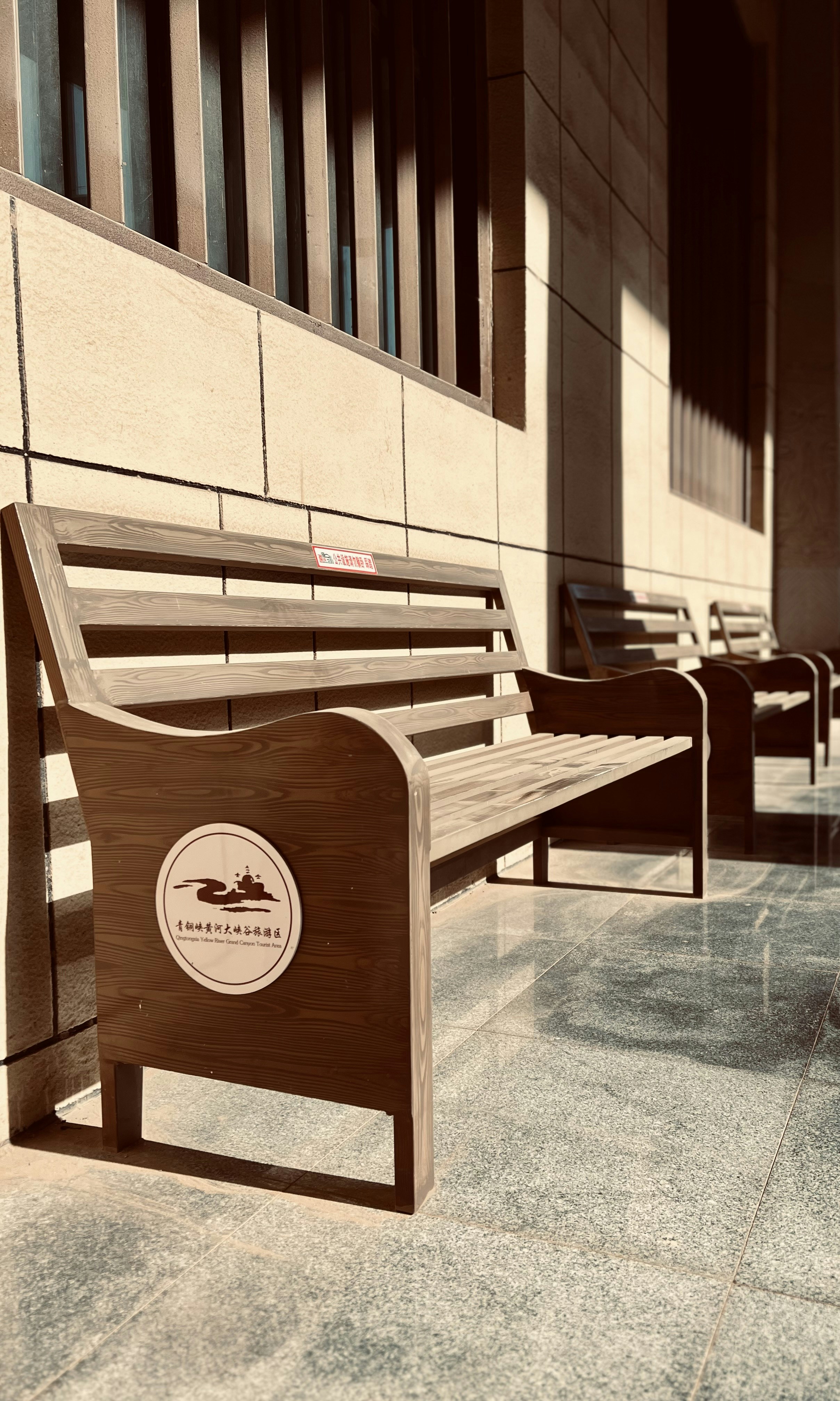 Sunlit Row of Benches Along a Modern Stone Facade