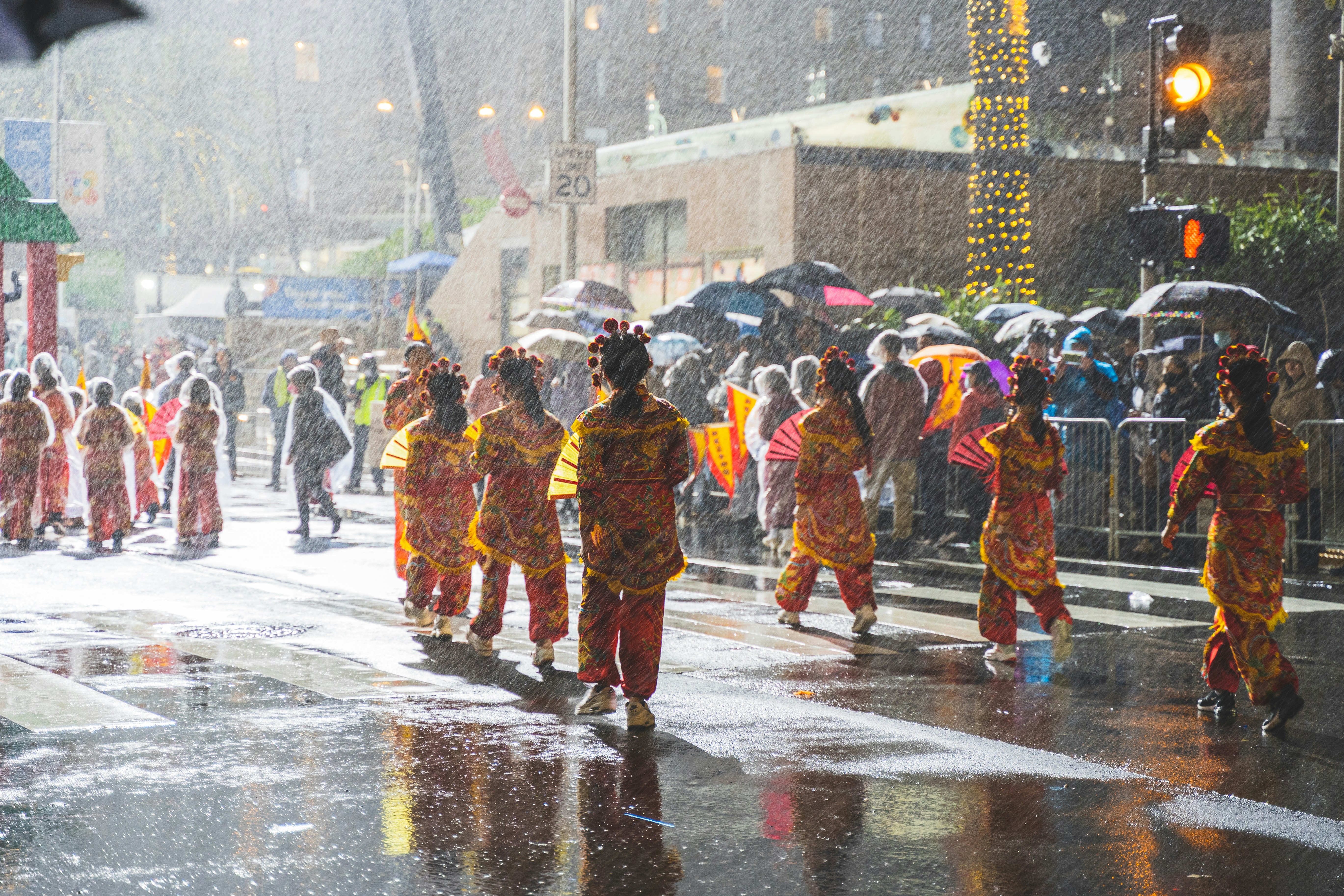 Yellow-clad dancers march through rain-lit city streets