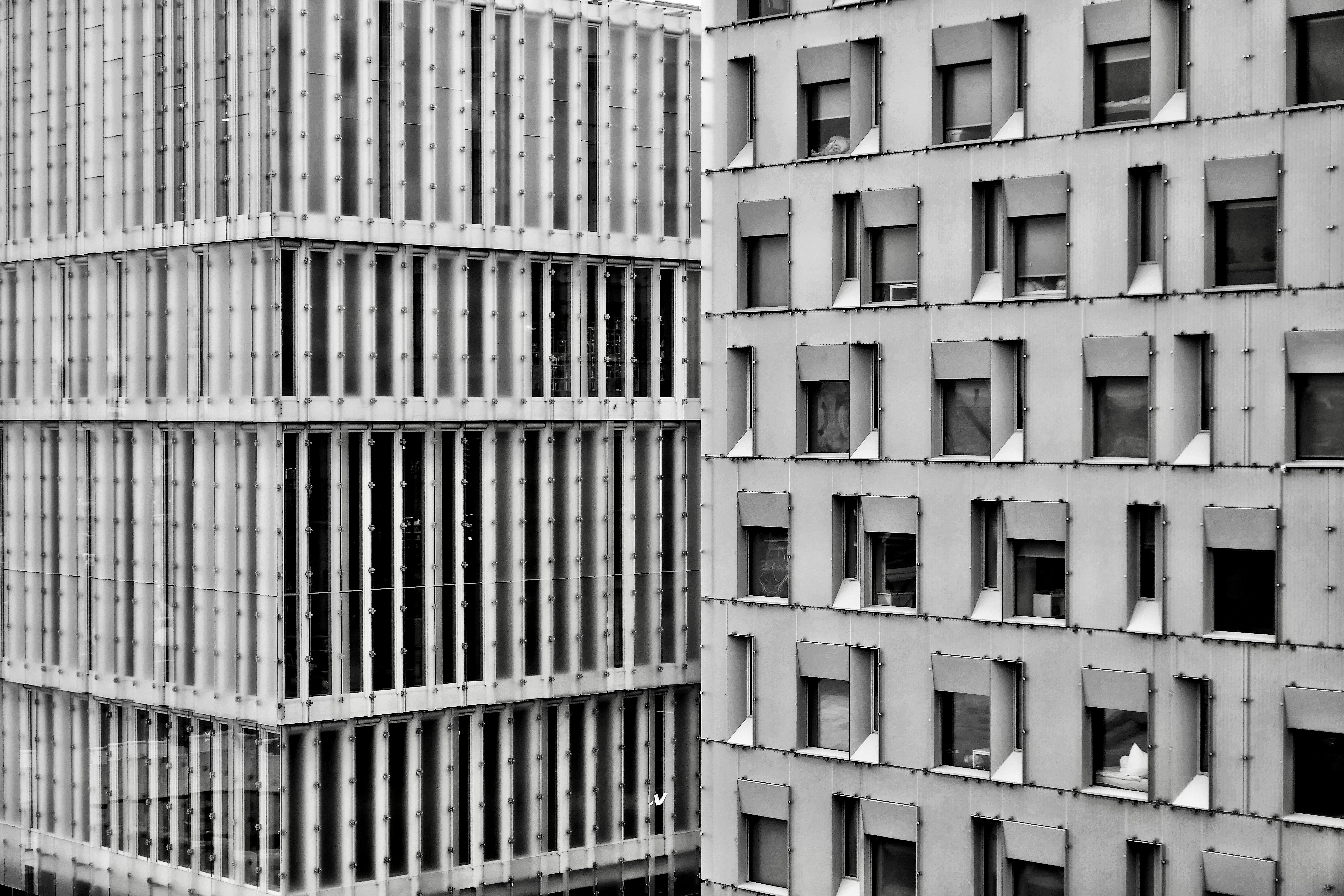 Two adjacent skyscrapers display contrasting architectural patterns in black and white.