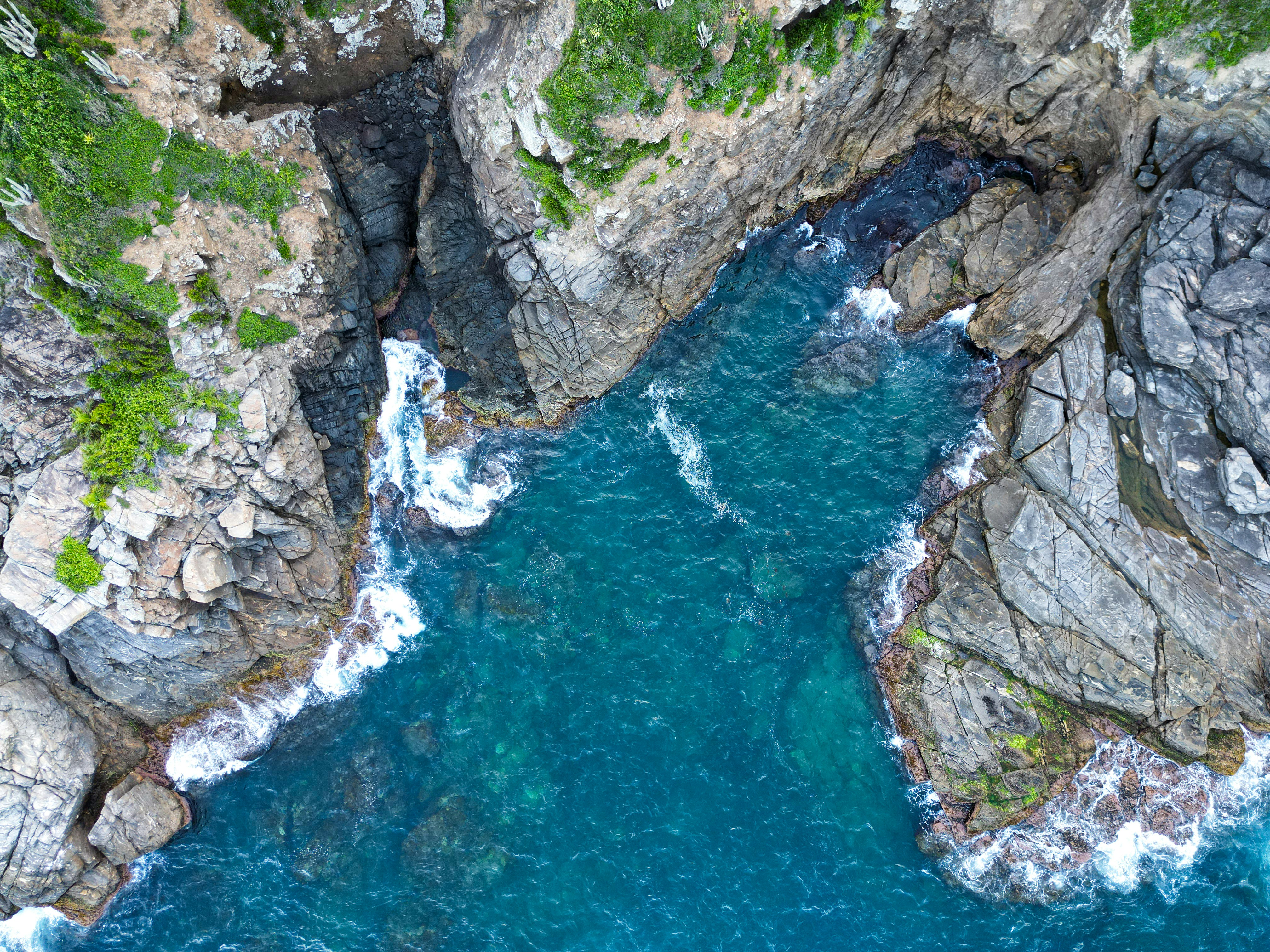 An aerial view of a body of water surrounded by rocks photo – Free ...
