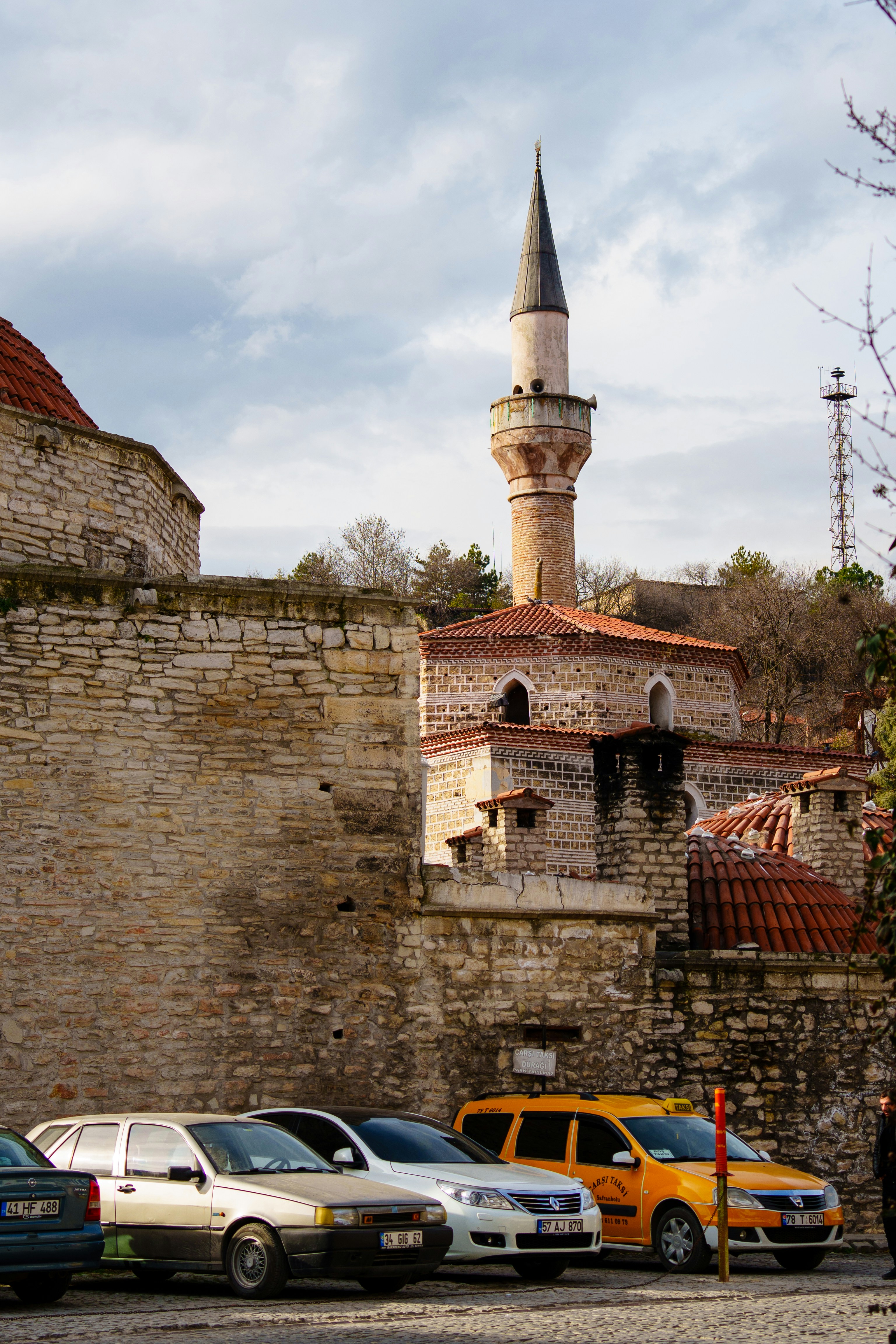 Stone Citadel Chronicles: Minaret Overlooking a Row of Parked Cars