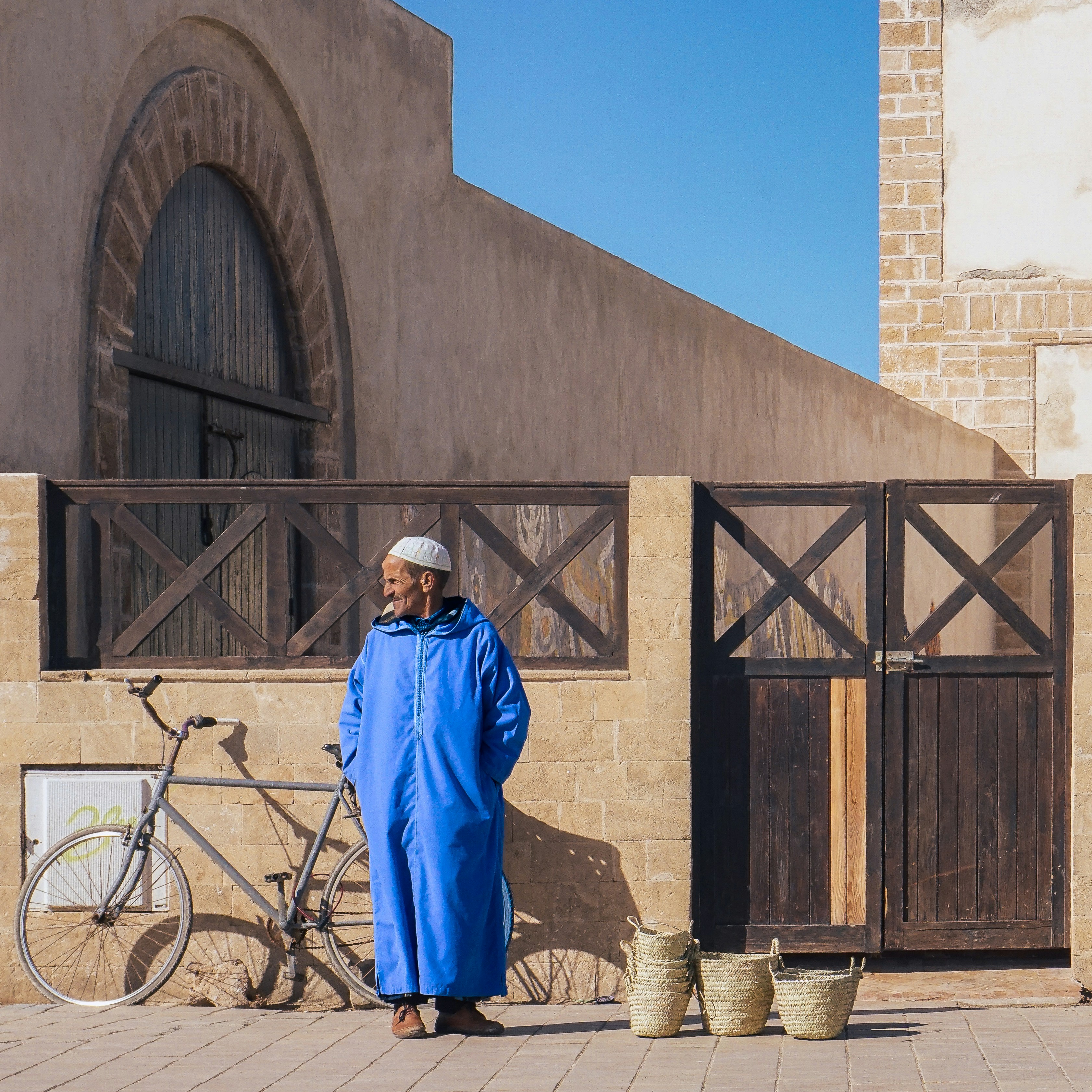Azure Garment beneath Arched Facade: A Quiet Portrait by the Bicycle