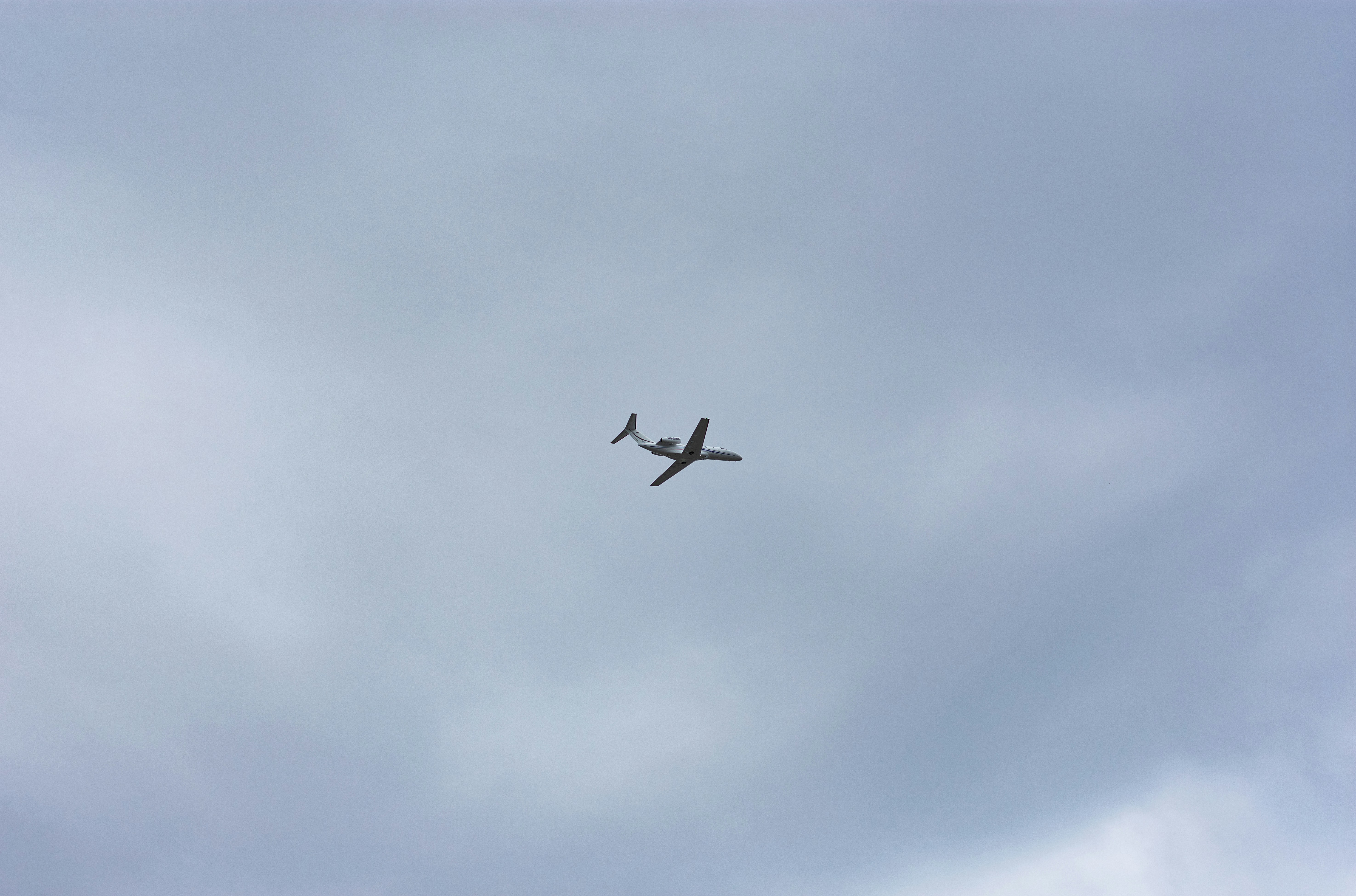 Airplane soaring through a cloudy sky with subtle lighting.