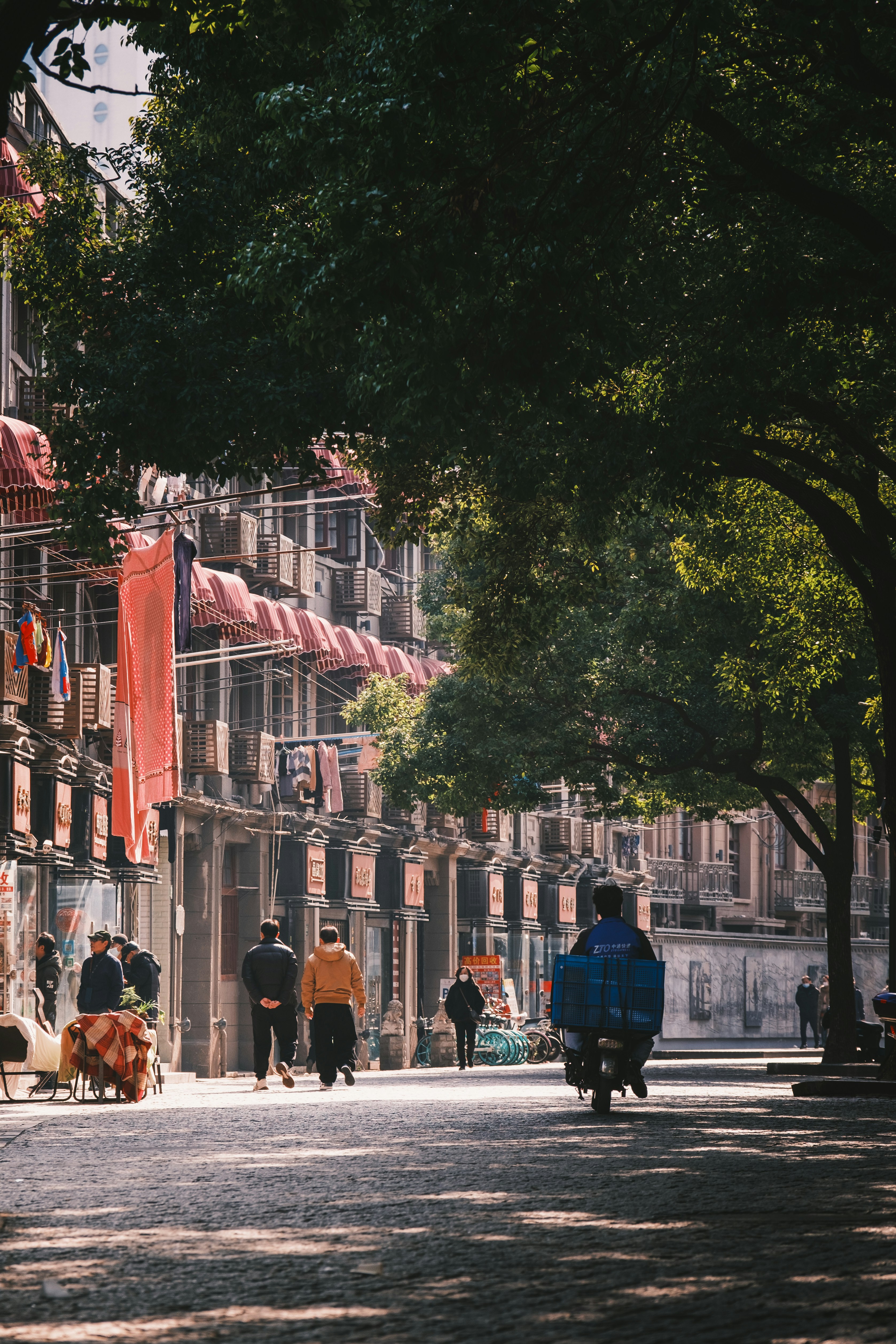 a group of people walking down a street next to tall buildings