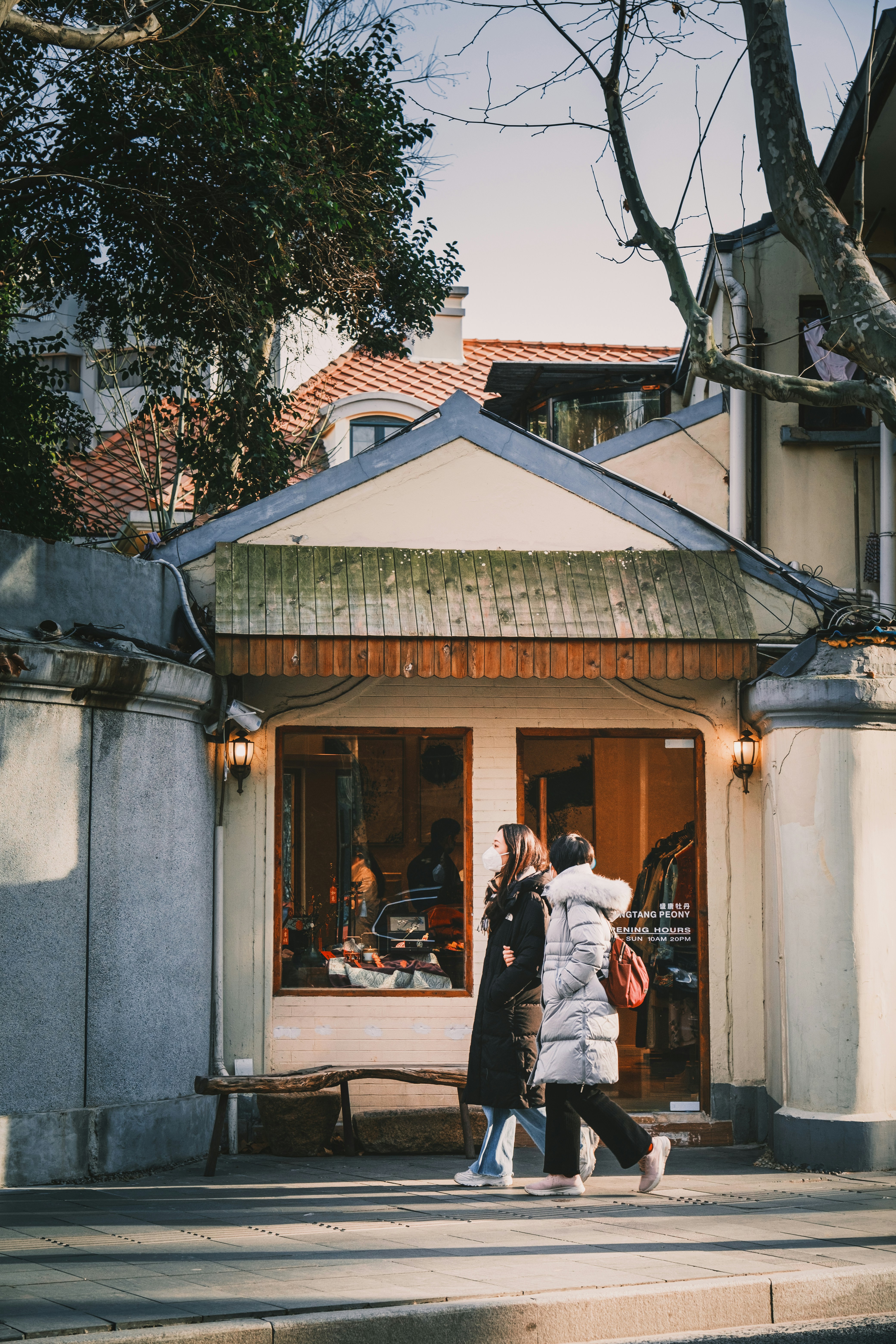 Threshold of Warmth: Two Shoppers Enter a Sunlit Café