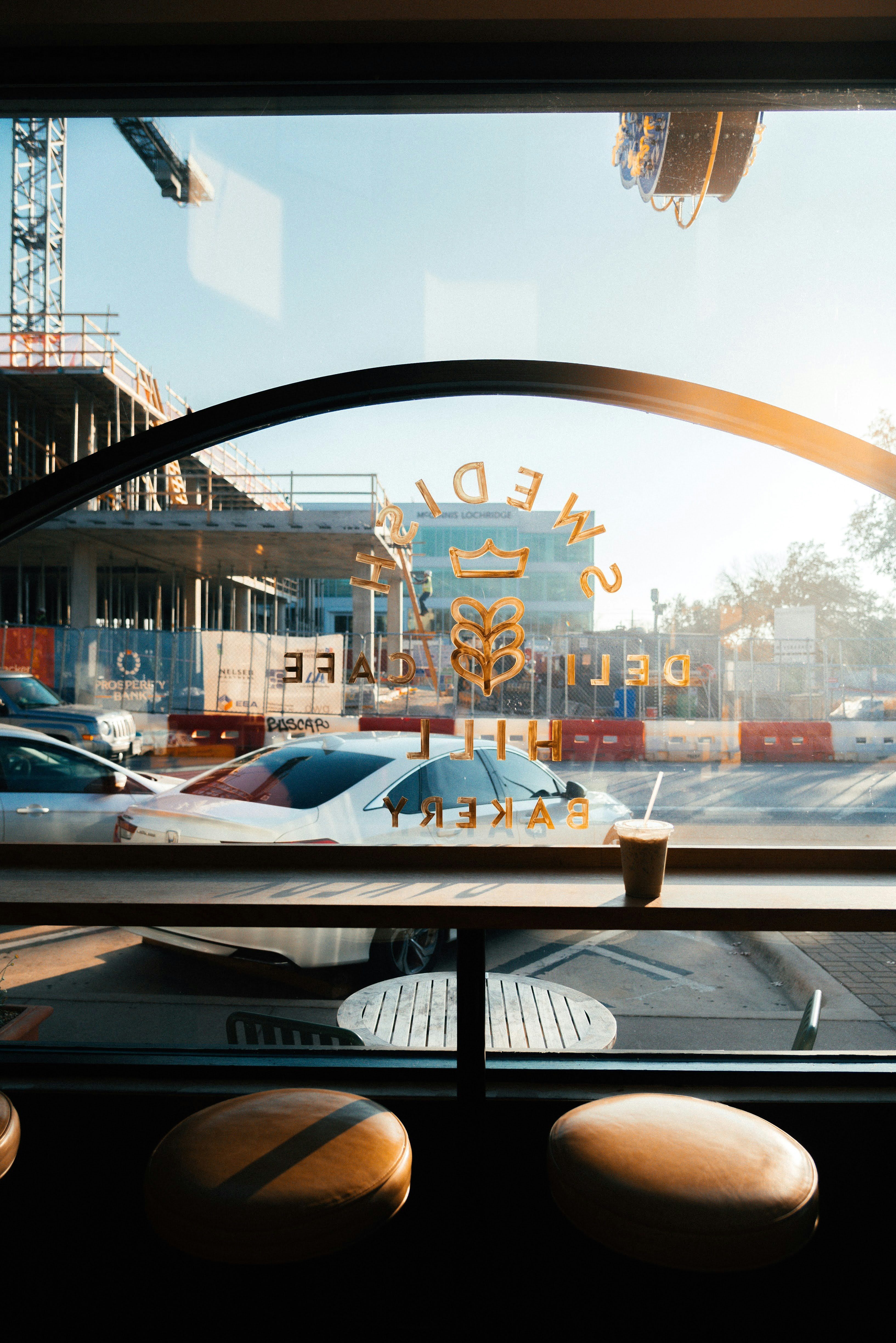 Arc of Light Over a Café Window: Construction and Coffee in Frame