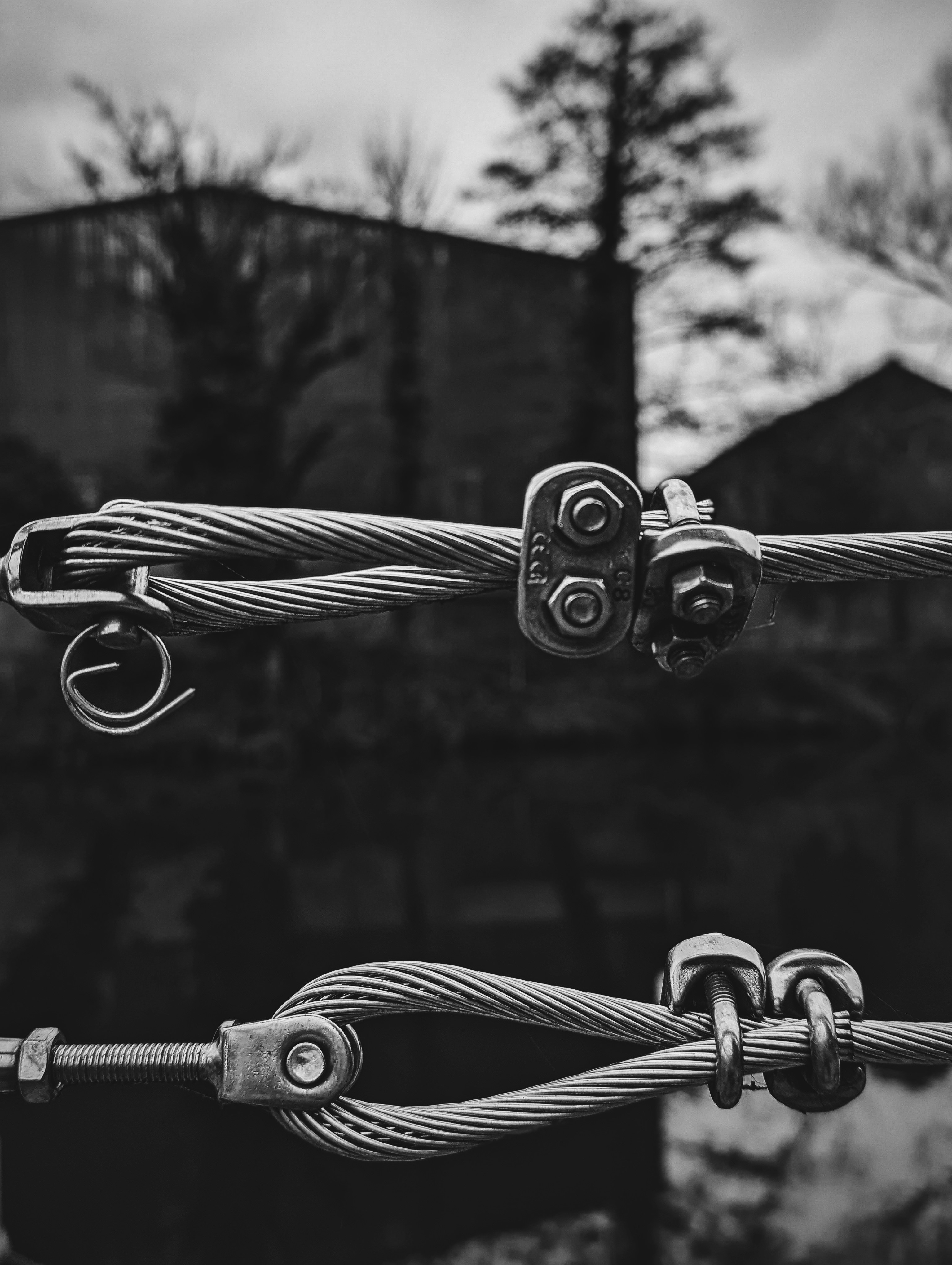 Close-up of metal wire connectors against a blurred industrial backdrop, showcasing intricate details and textures.