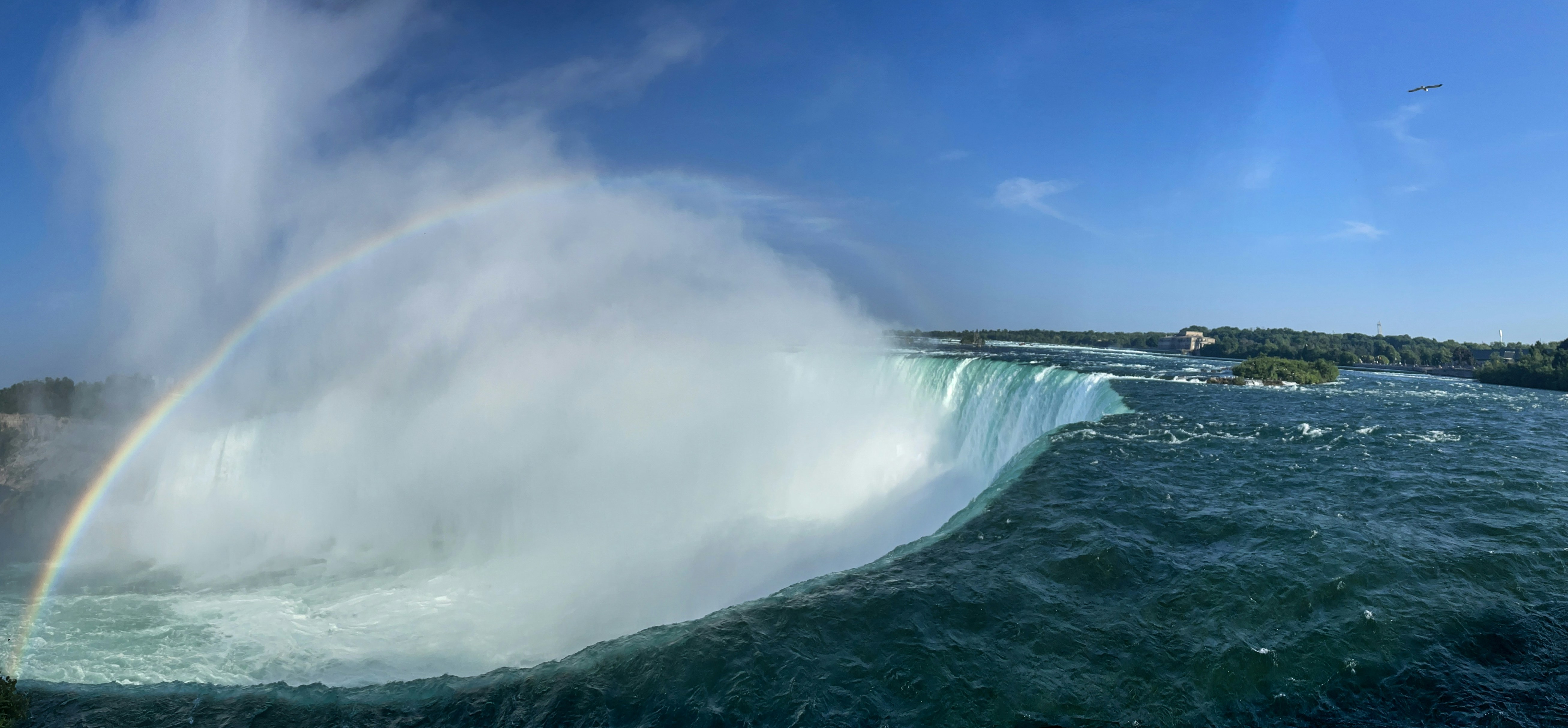 Majestic waterfall cascading with a vibrant rainbow arching over the misty spray. The image captures the dynamic interplay of water and light.