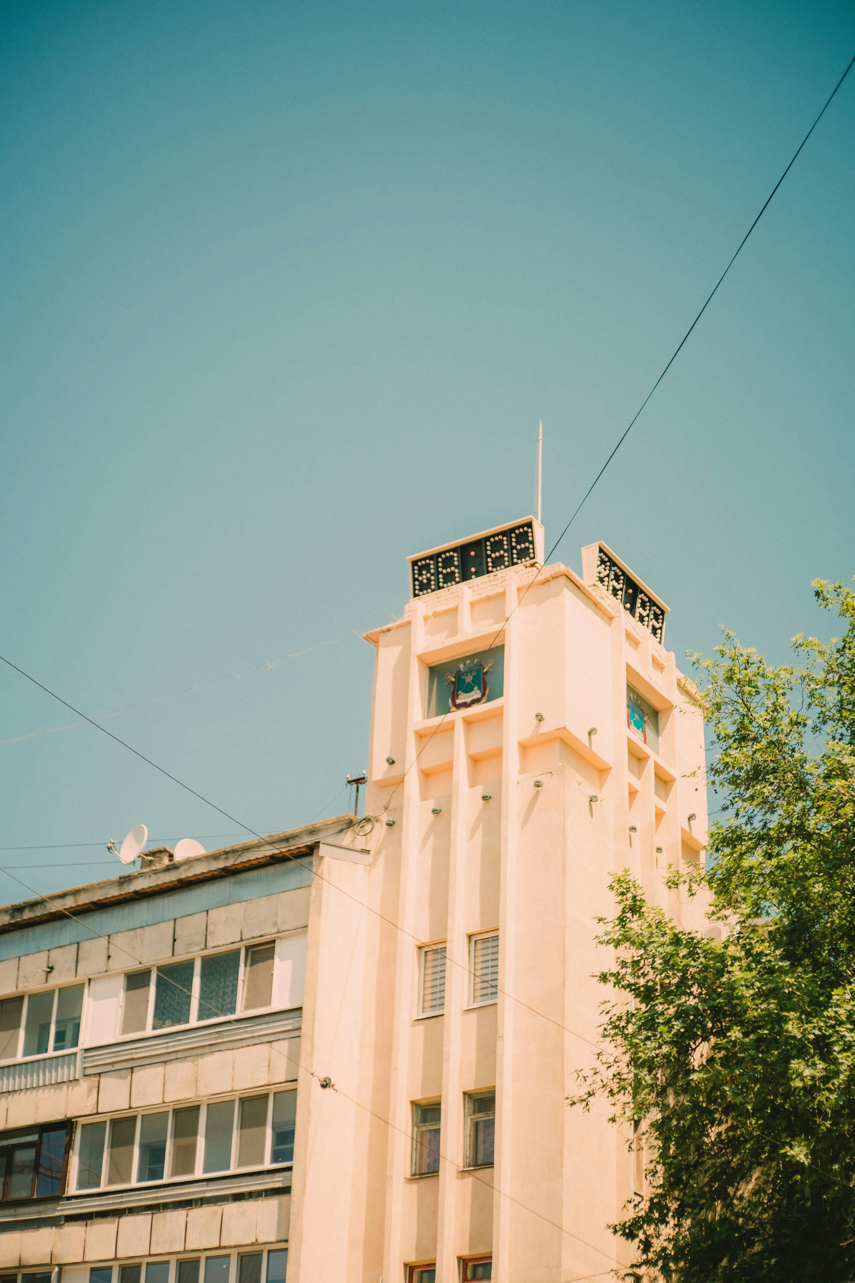 Pastel Clock Tower: A Sunlit Art Deco Beacon Against a Cyan Sky