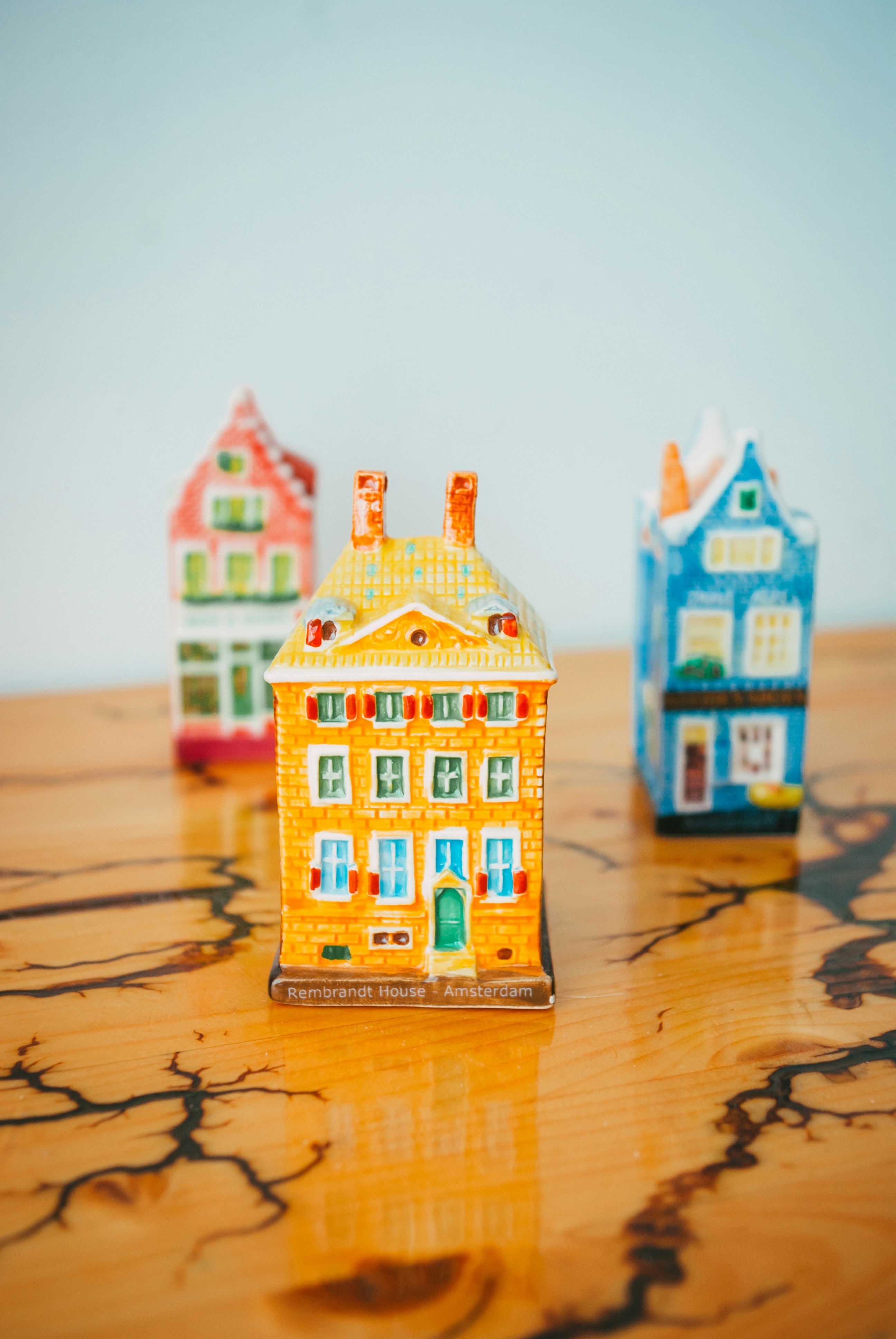 a wooden table topped with three small toy houses