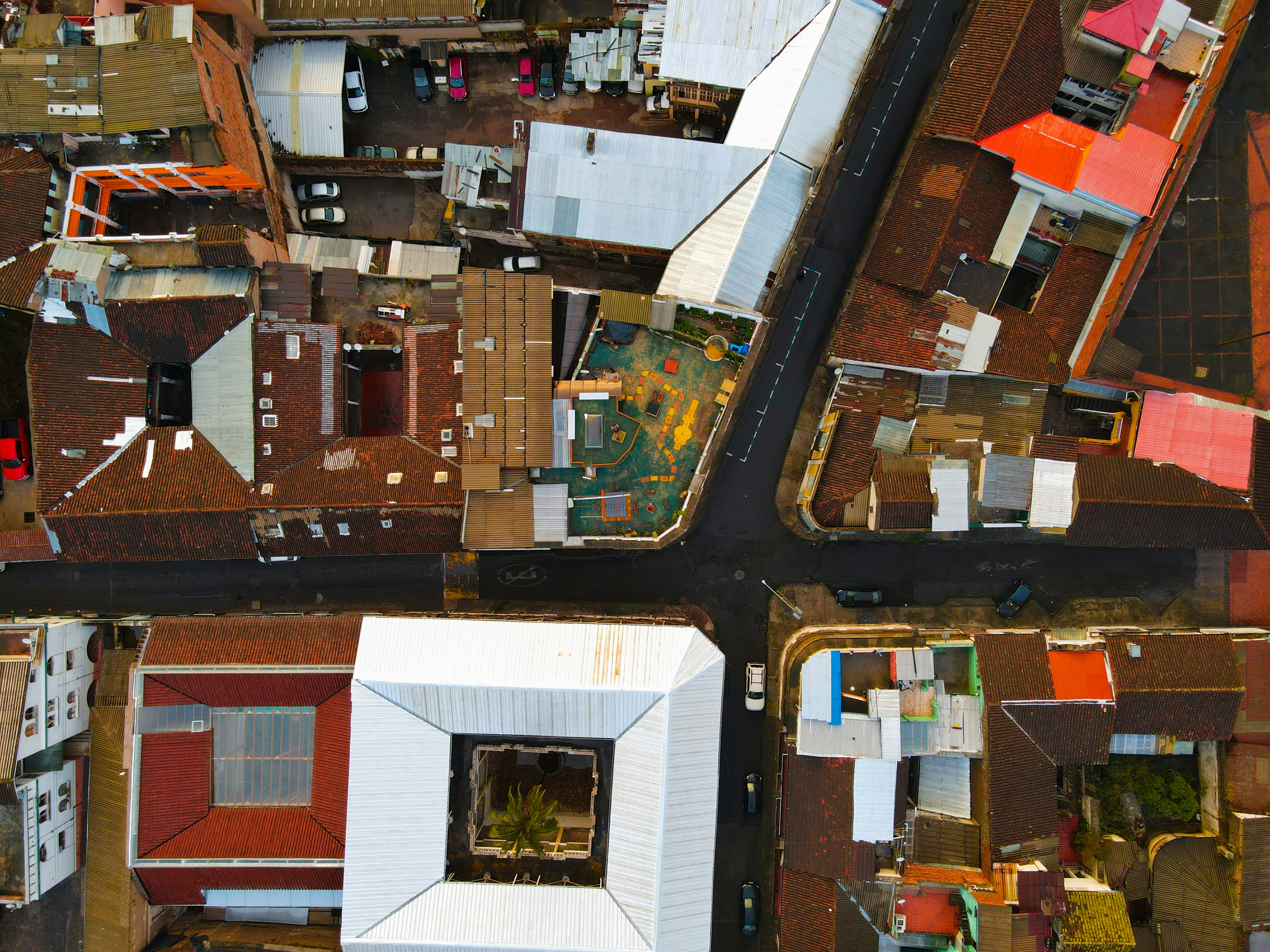 Aerial view of intersecting streets and colorful rooftops in a compact cityscape.