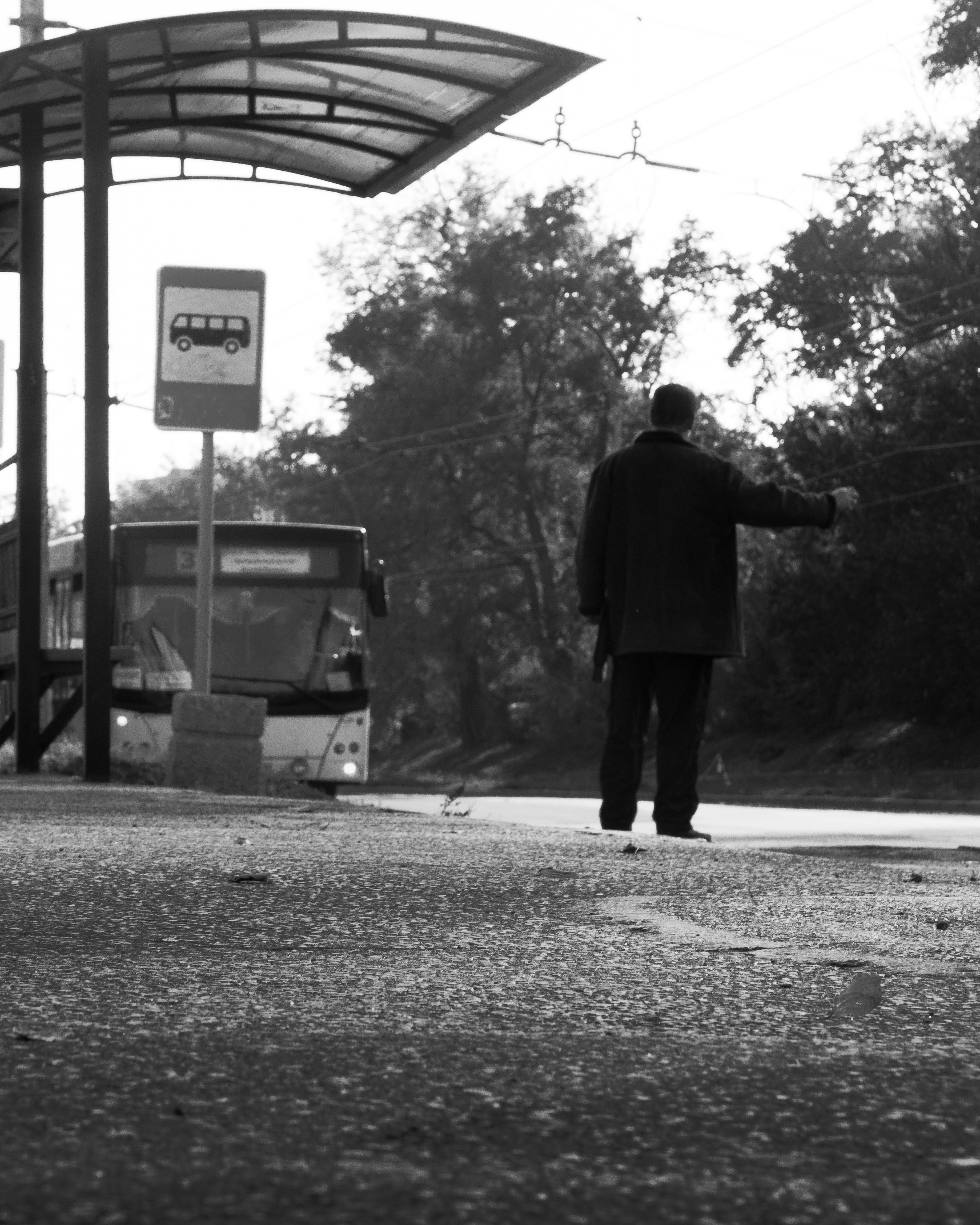Une photo en noir et blanc d’un homme attendant à un arrêt de bus photo ...