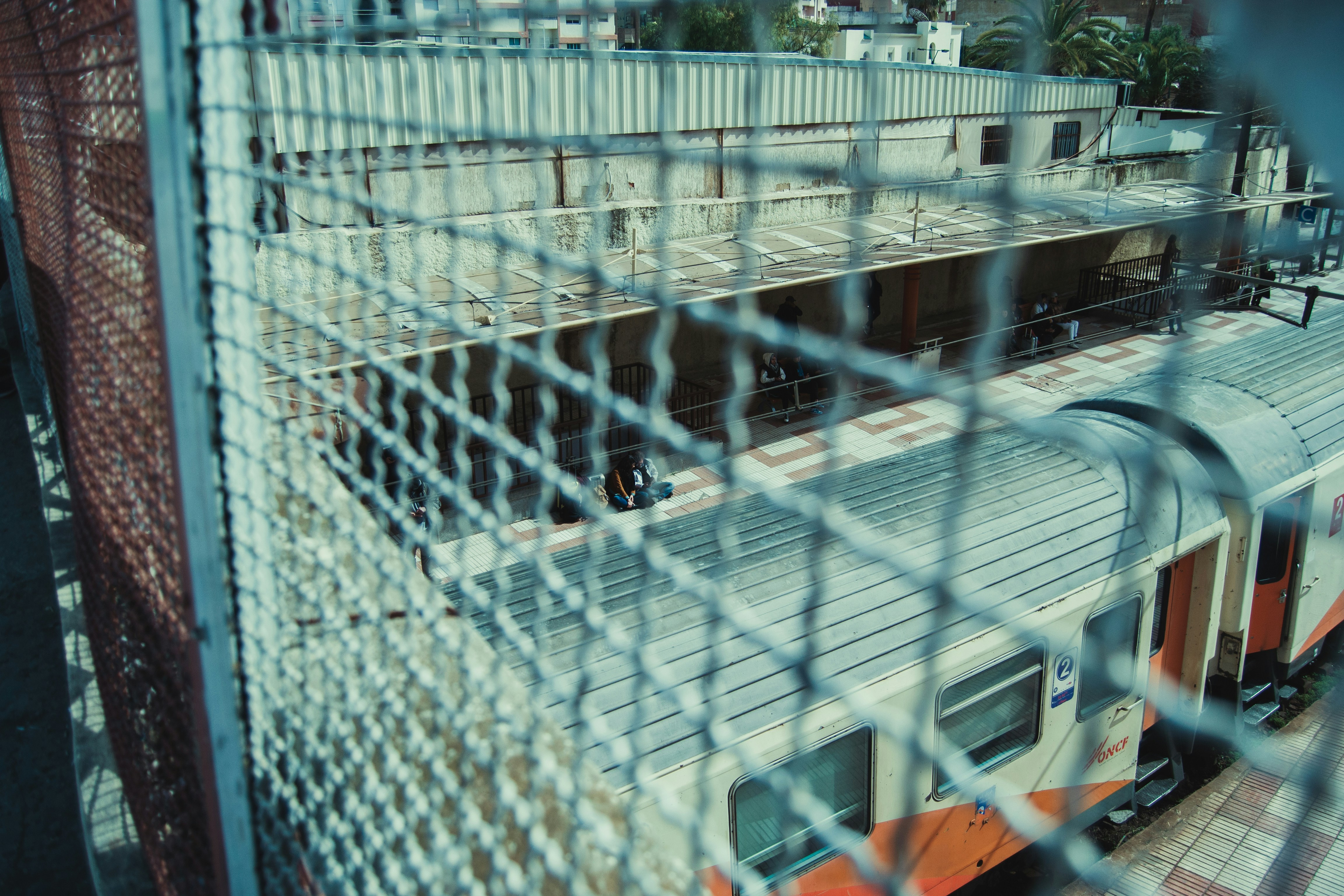 A view of a train through a chain link fence photo – Free Train Image ...