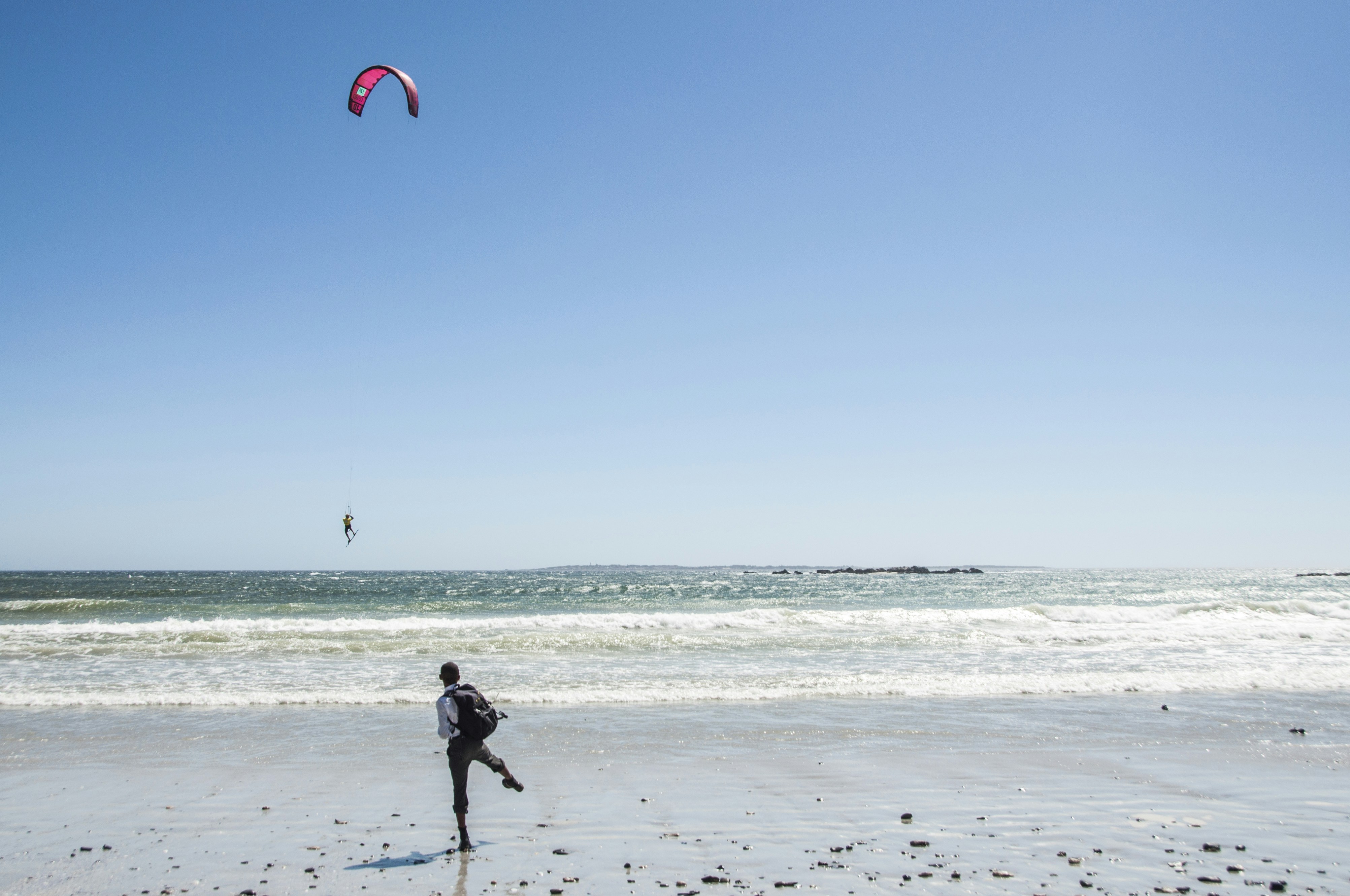 Stride and Surf: A Beach Runner Meets a Distant Kite Surfer