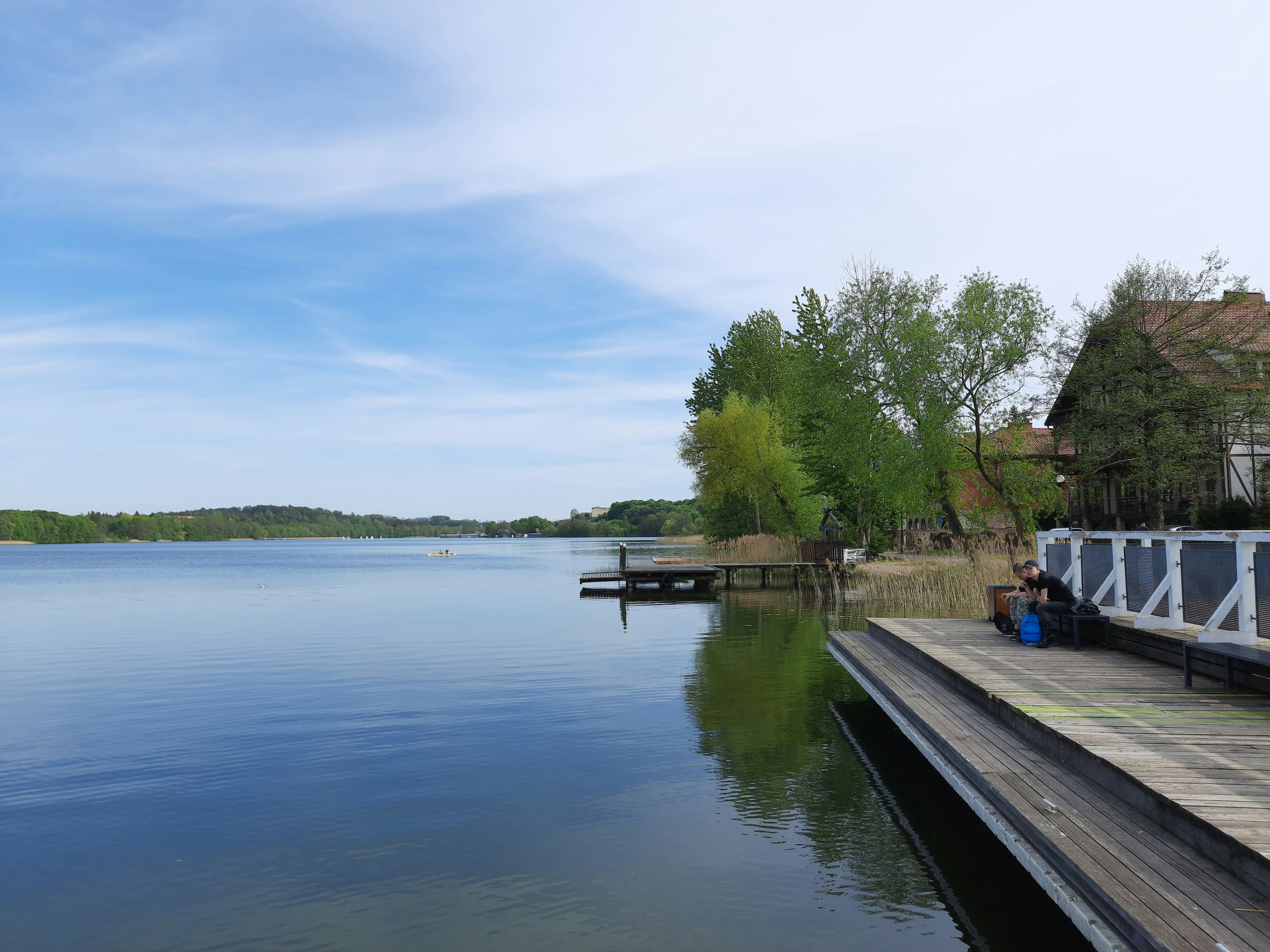 Tranquil lake scene with lush greenery and wooden docks reflecting on the calm water surface.