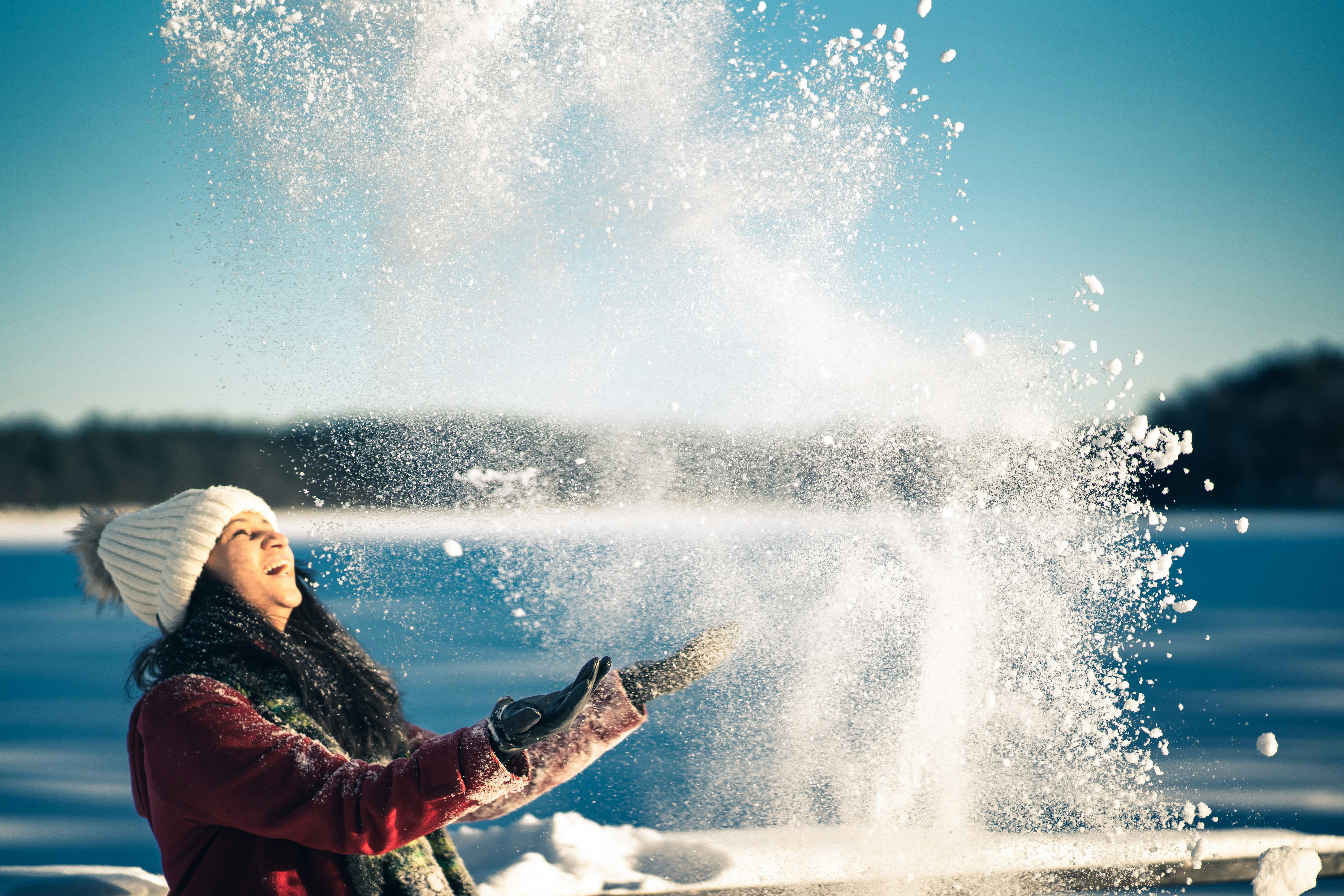A woman in a red jacket throwing snow into the air photo – Free Winter ...