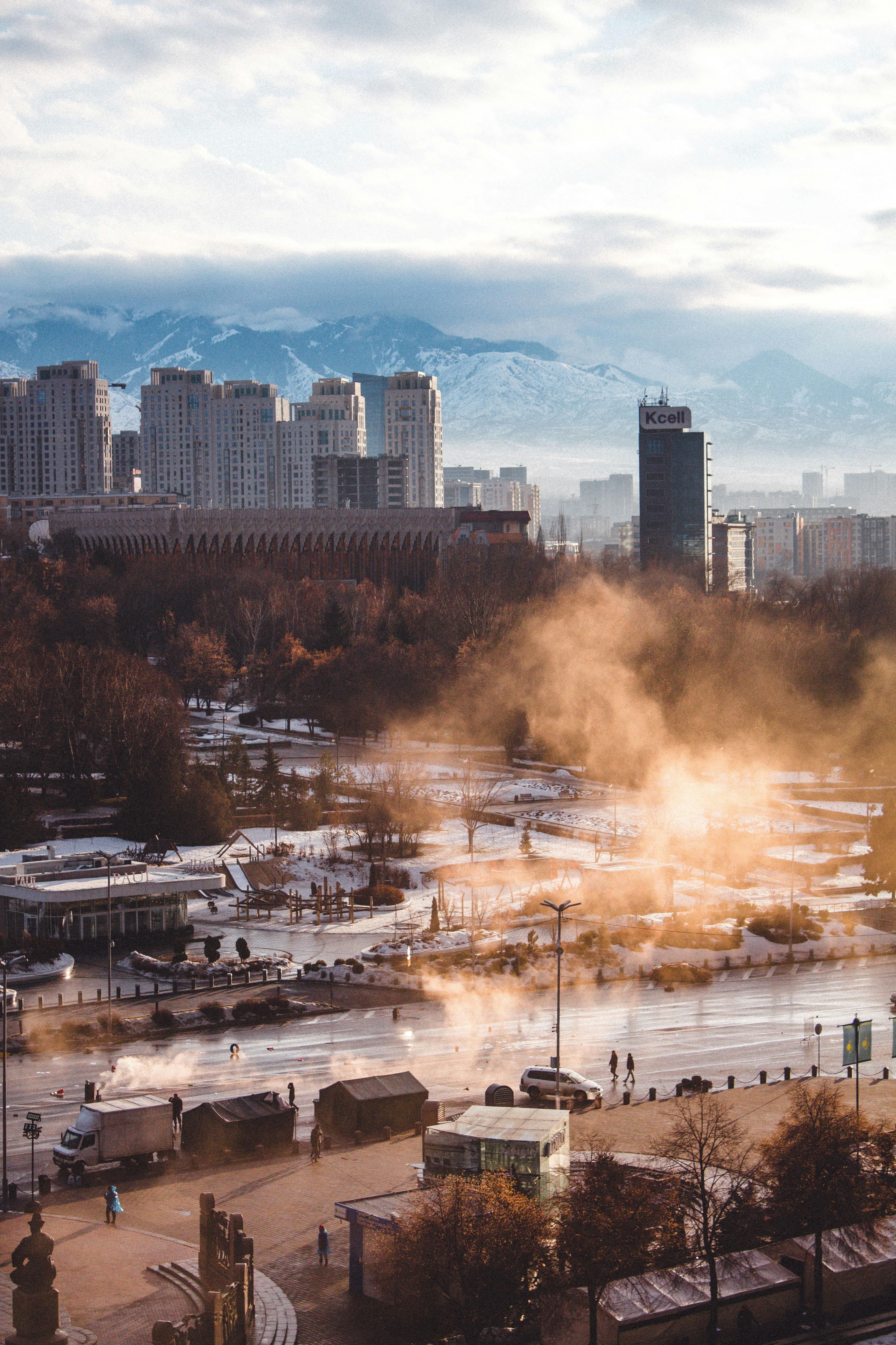 Steam Plumes Over a Winter Cityscape Framed by Snowy Peaks
