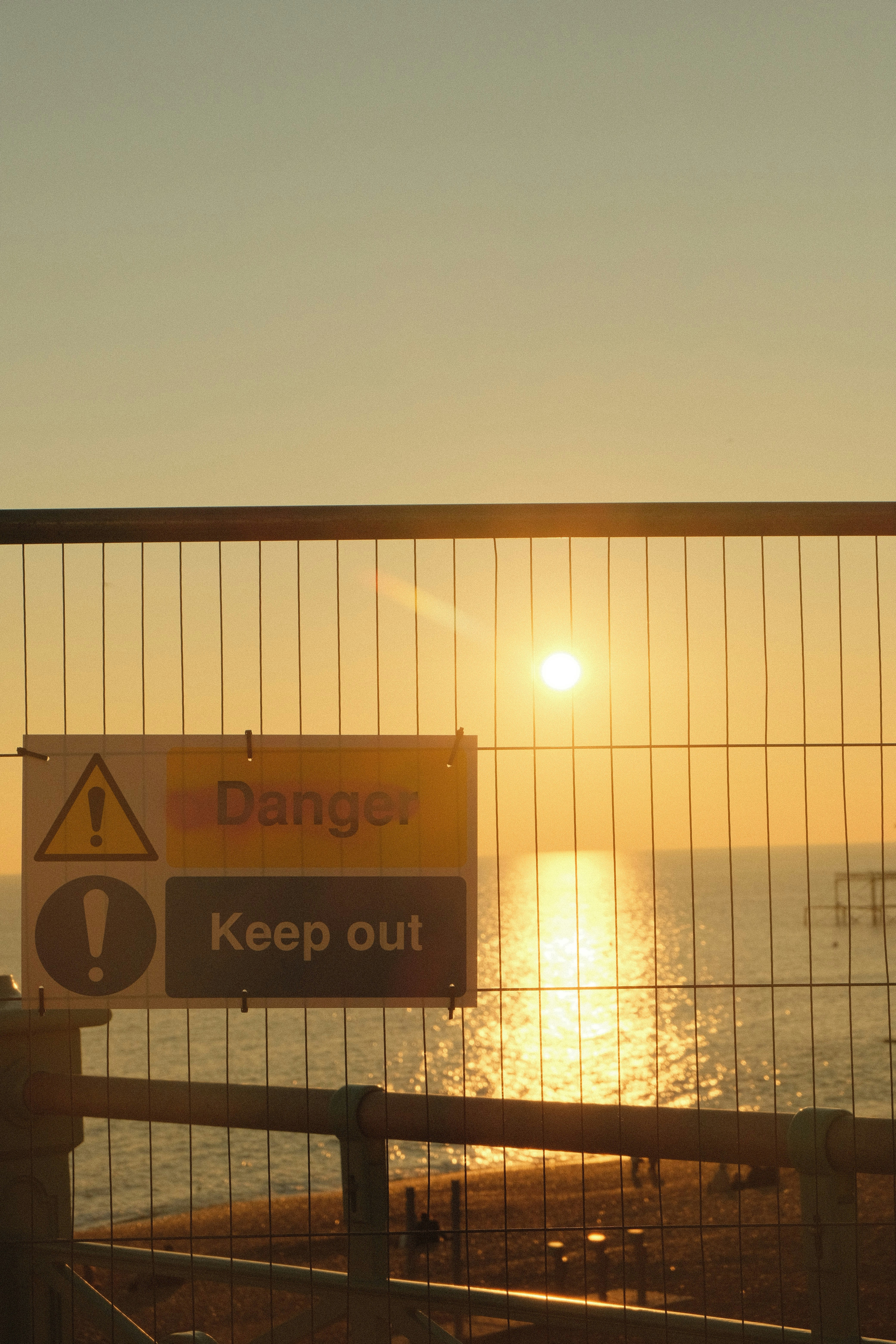 Sun over the Seaside Barrier: A Quiet Golden Hour by the Fence