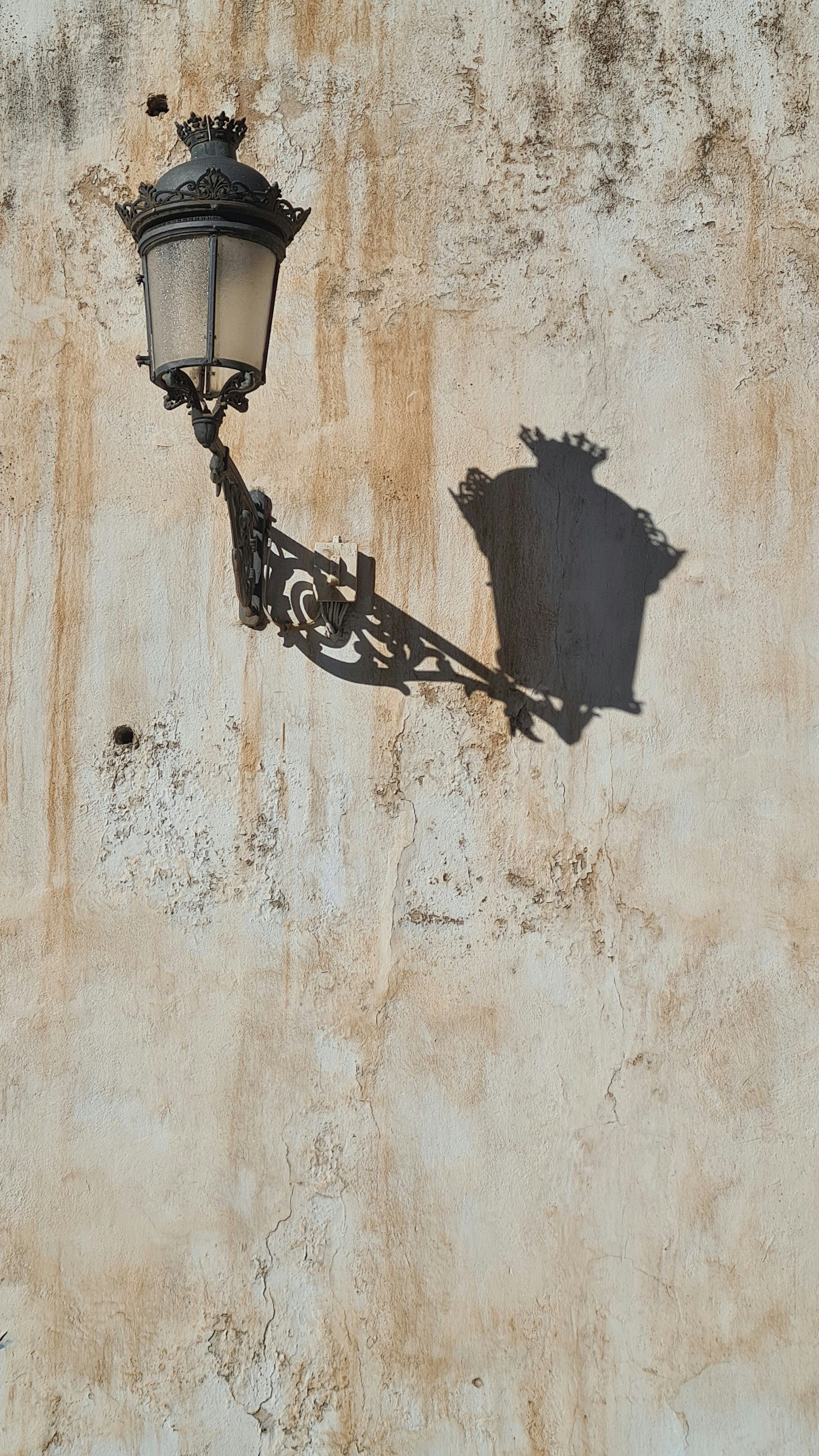 Iron Lantern Shadow: A Sunlit Portrait on Weathered Stucco