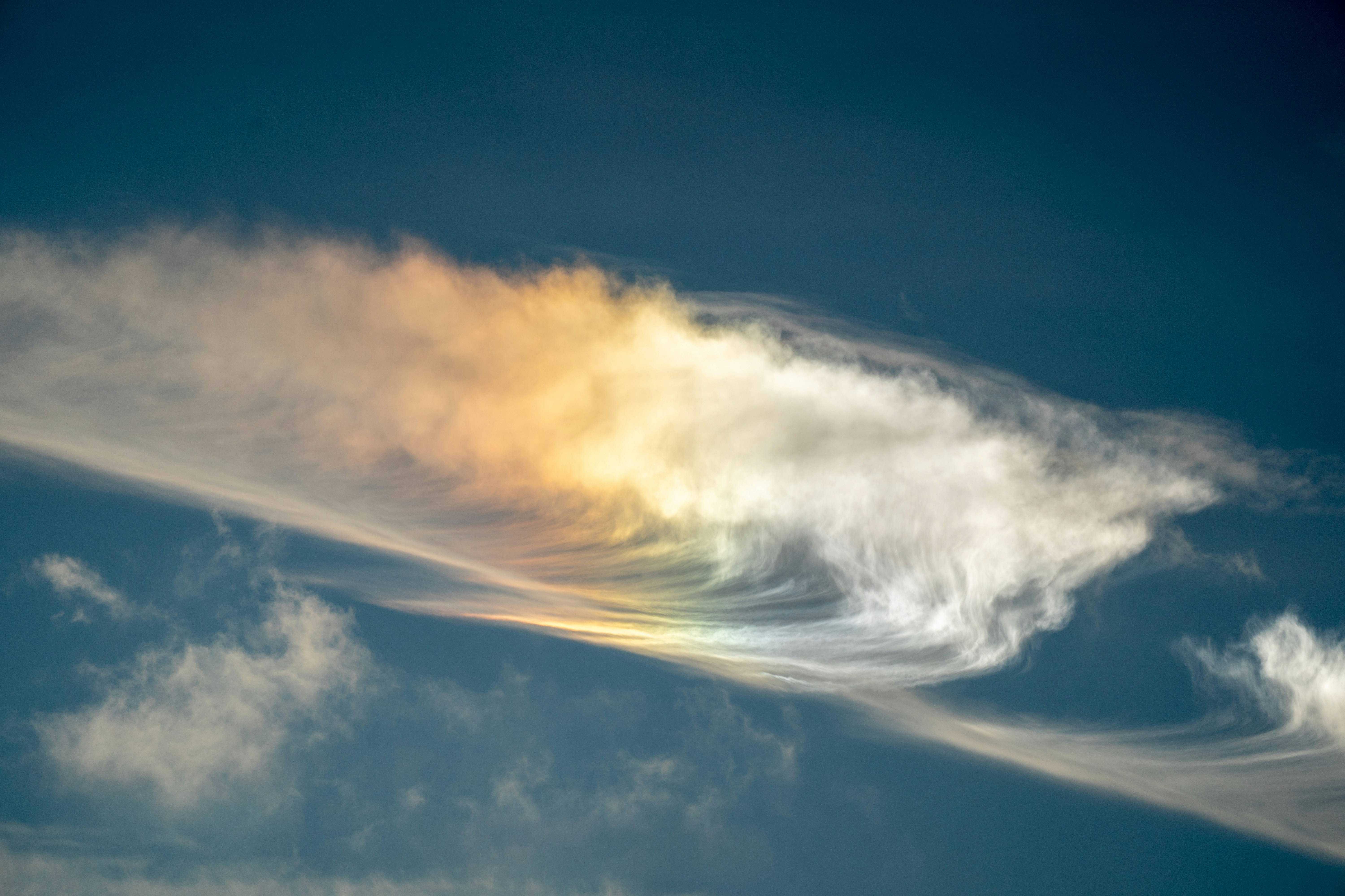 A vibrant cloud formation displaying a spectrum of colors against a deep blue sky, hinting at the beauty of atmospheric phenomena.