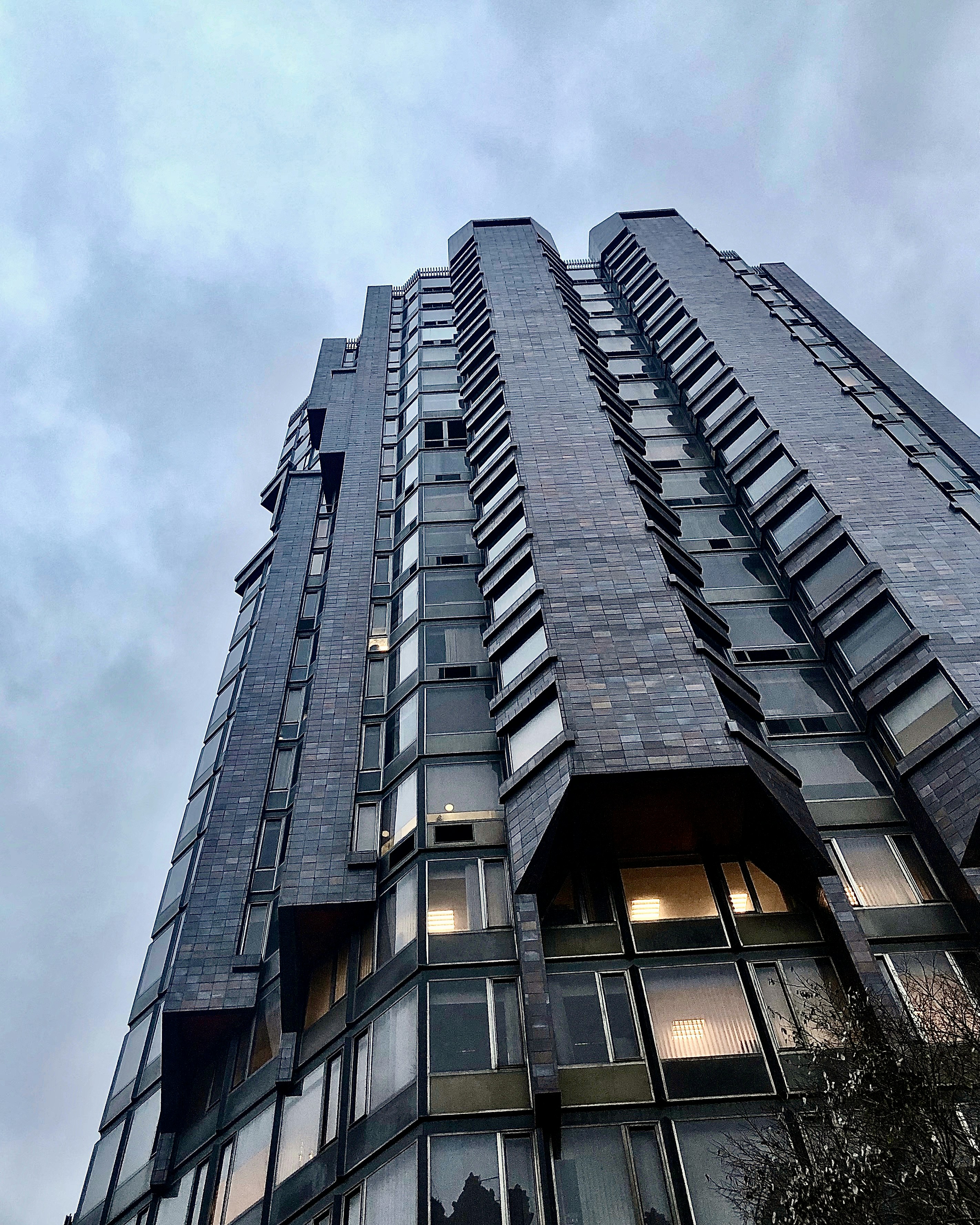 Skyward Facades: A Geometric Tower Reaches for the Clouded Sky