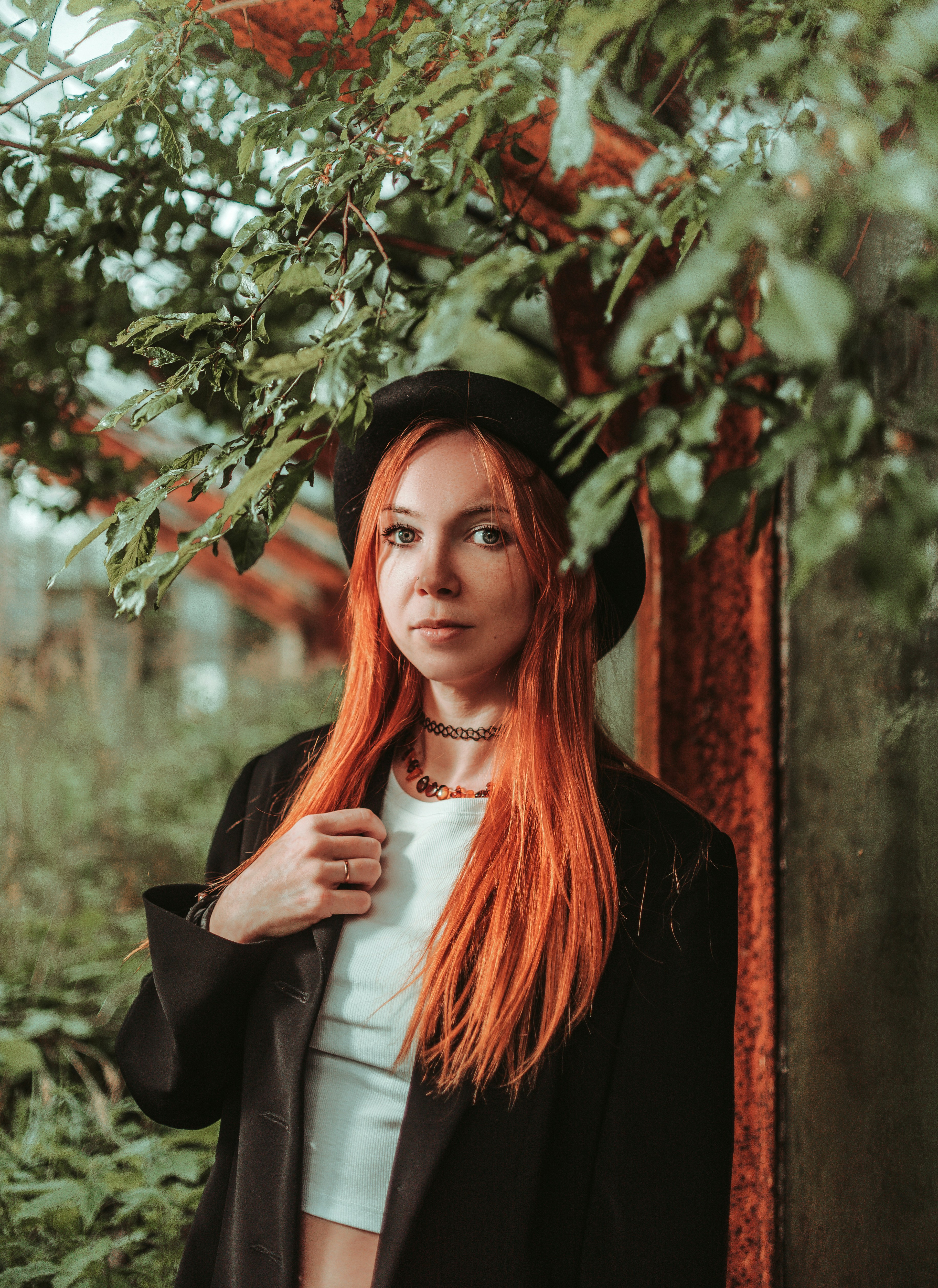 Crimson Portrait Beneath a Green Canopy and Rusted Iron