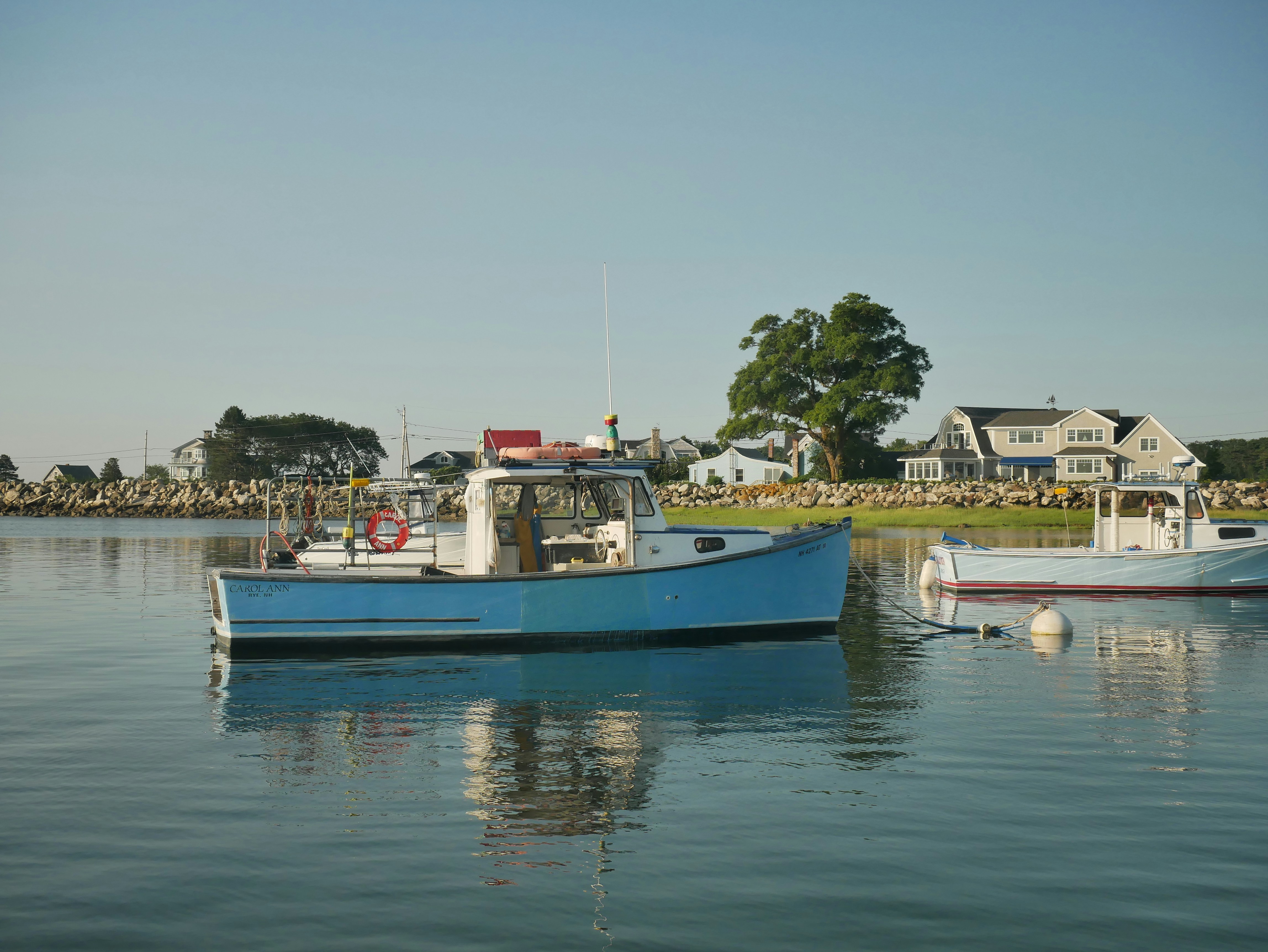 Blue-Hulled Boat Anchored in a Quiet Harbor, Reflections on Glassy Water
