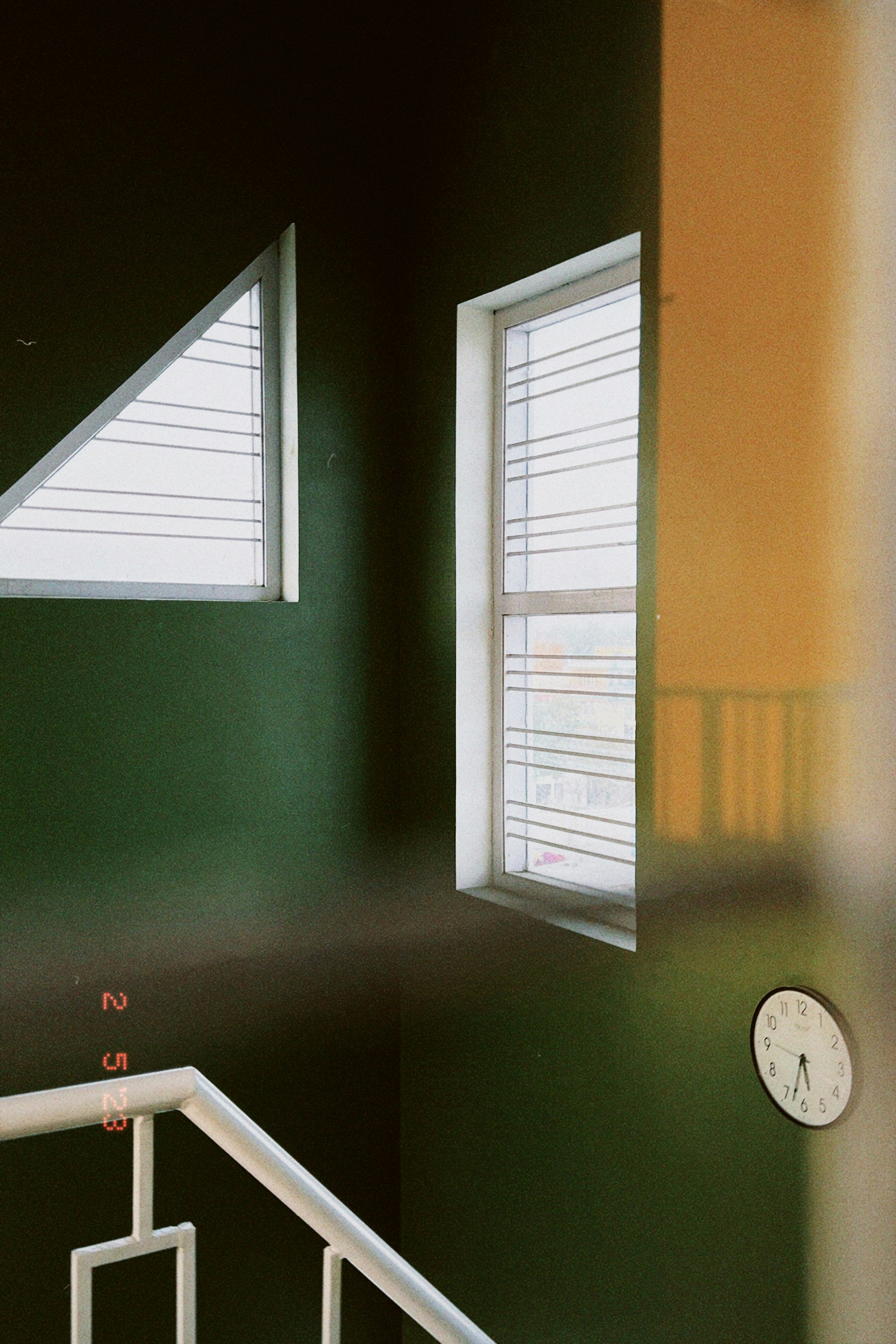 Rectilinear Light: Tall Windows Framing a Quiet Green Stairwell