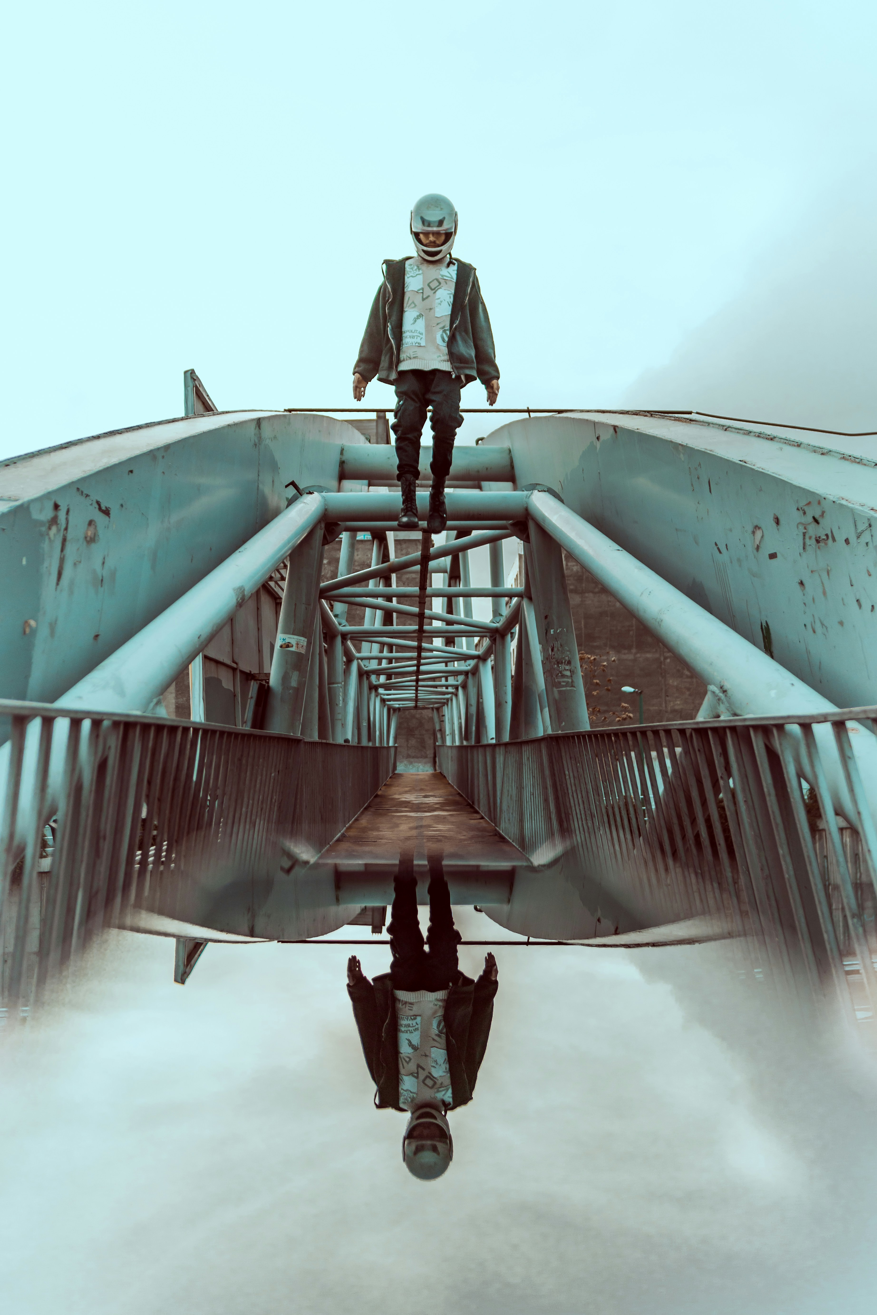 Edge of Steel: A lone climber atop a weathered bridge, mirrored in the water